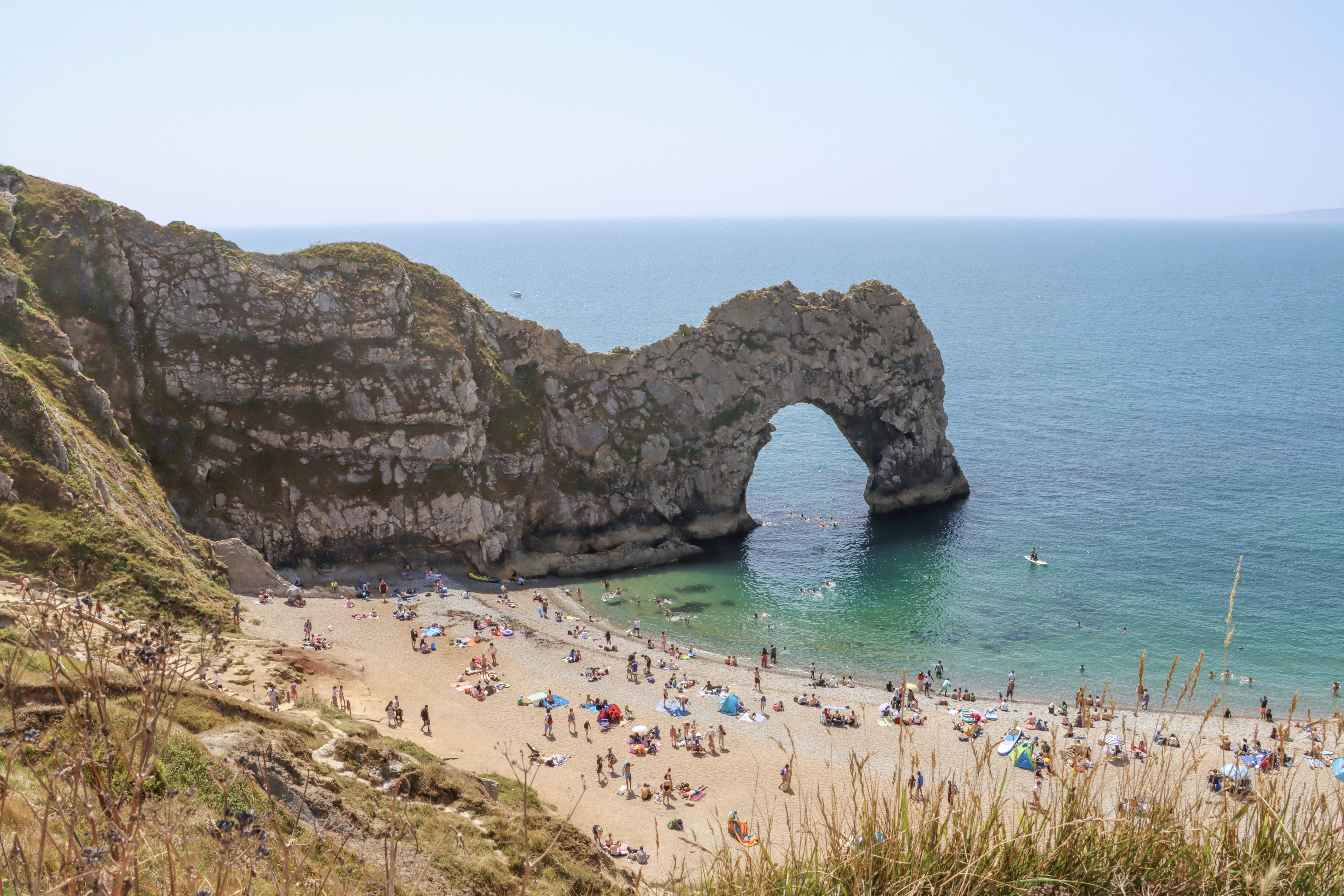 Durdle Door, Dorset, UK. Perfect summer day and a gorgeous spot in south west England. | Durdle door arch and busy beach on a sunny day.