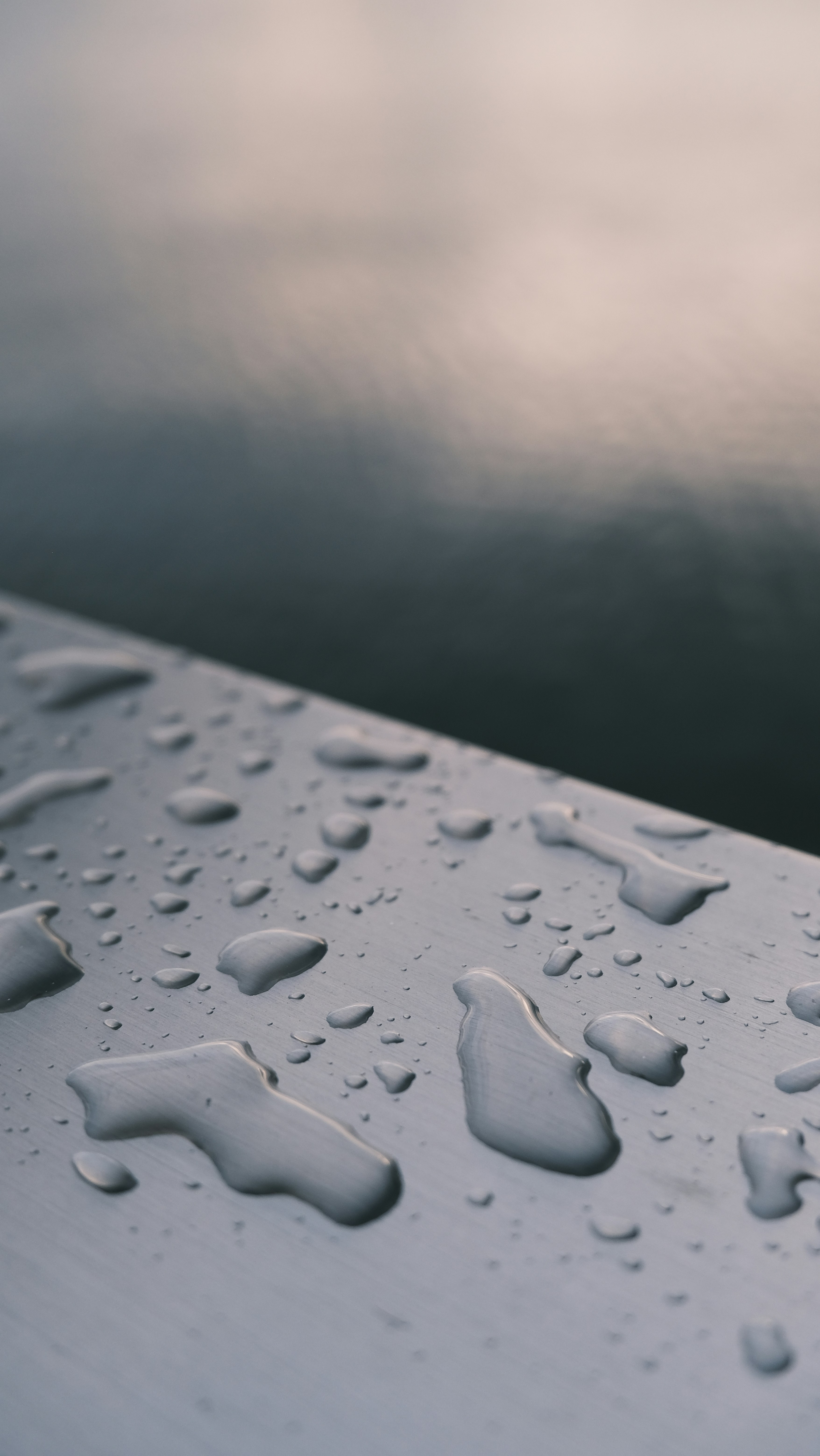 Raindrops on a metallic surface with blurred background