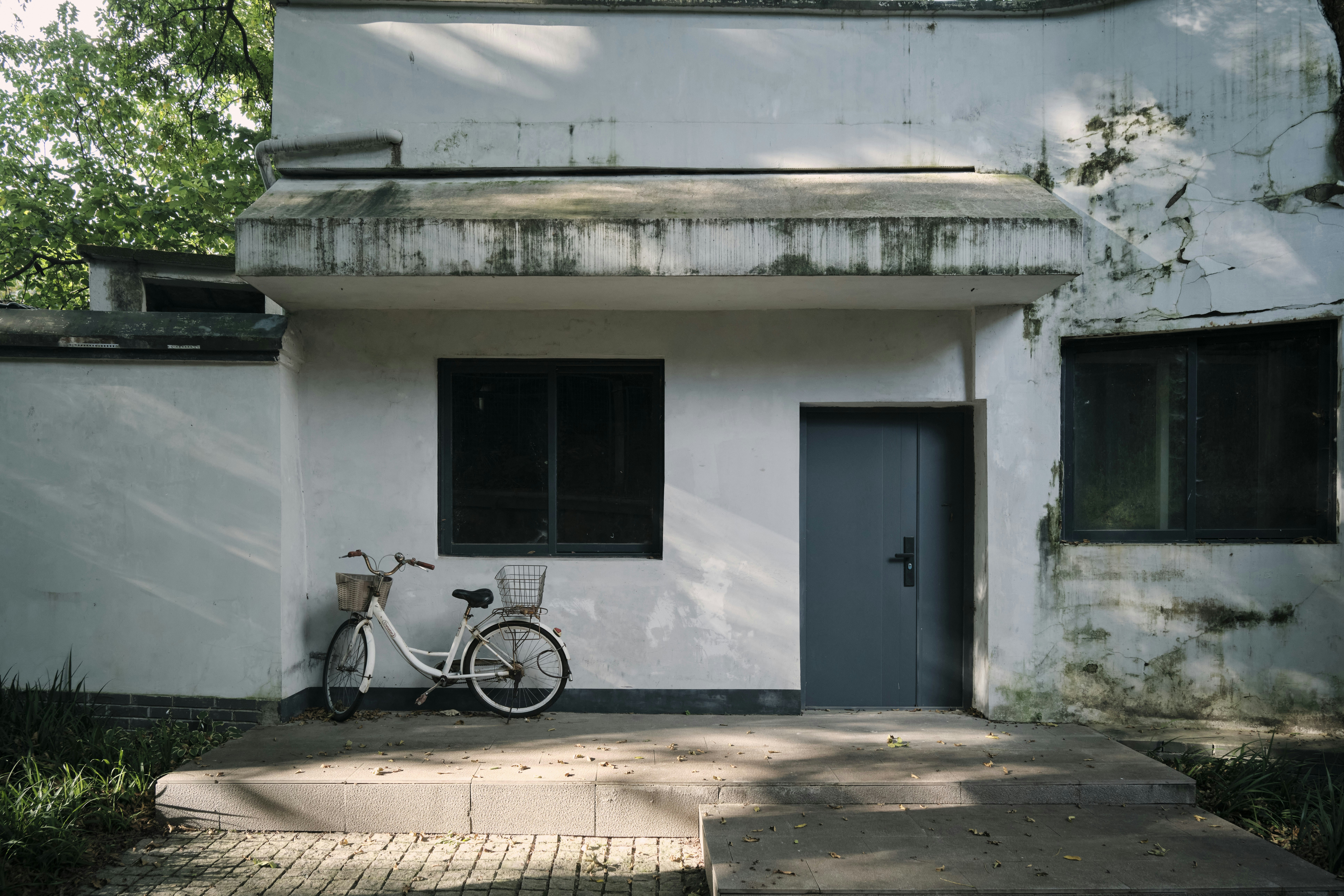 White bicycle parked outside a weathered building.