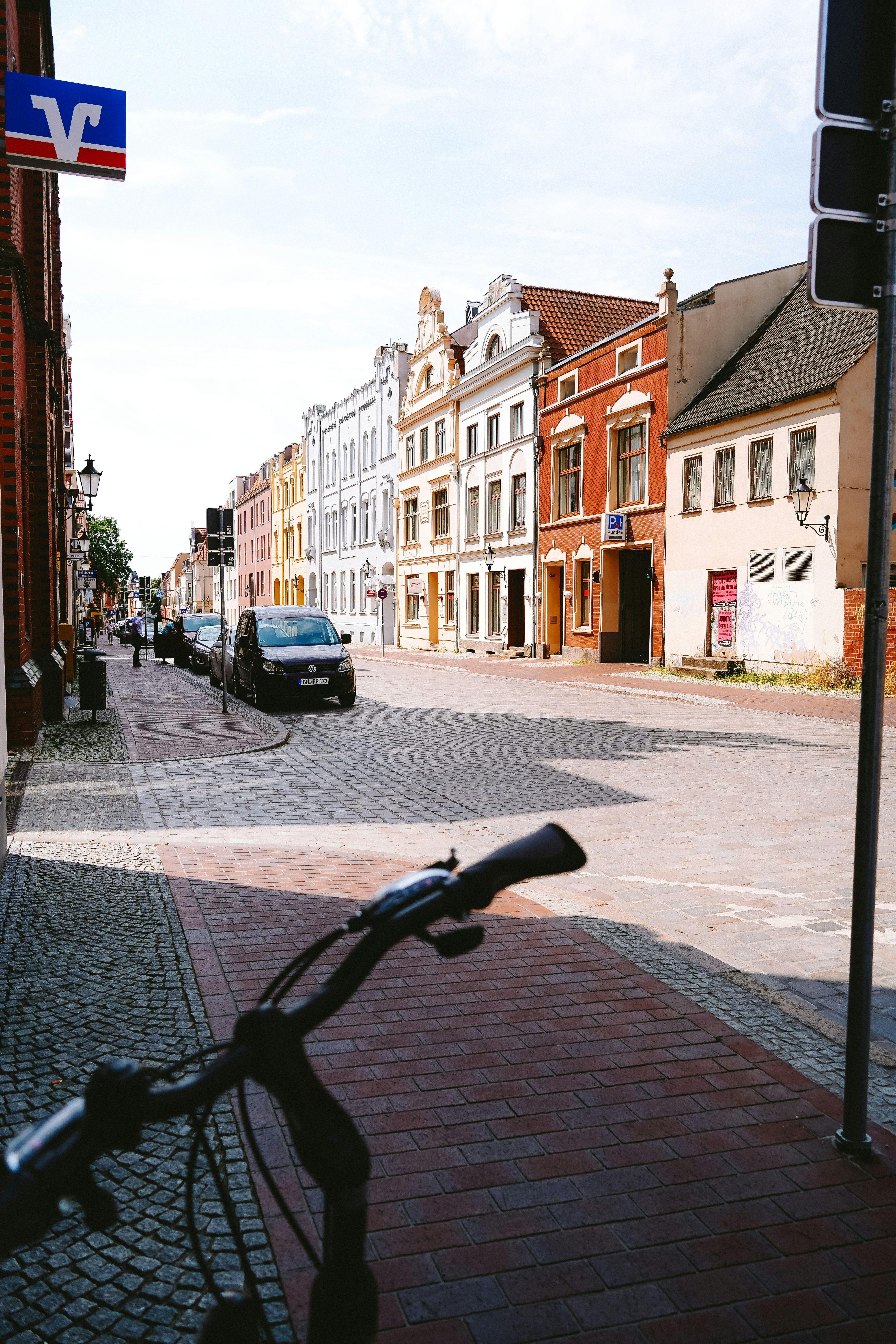 bicycle on old empty street | Bicycle handlebars in foreground of european street scene