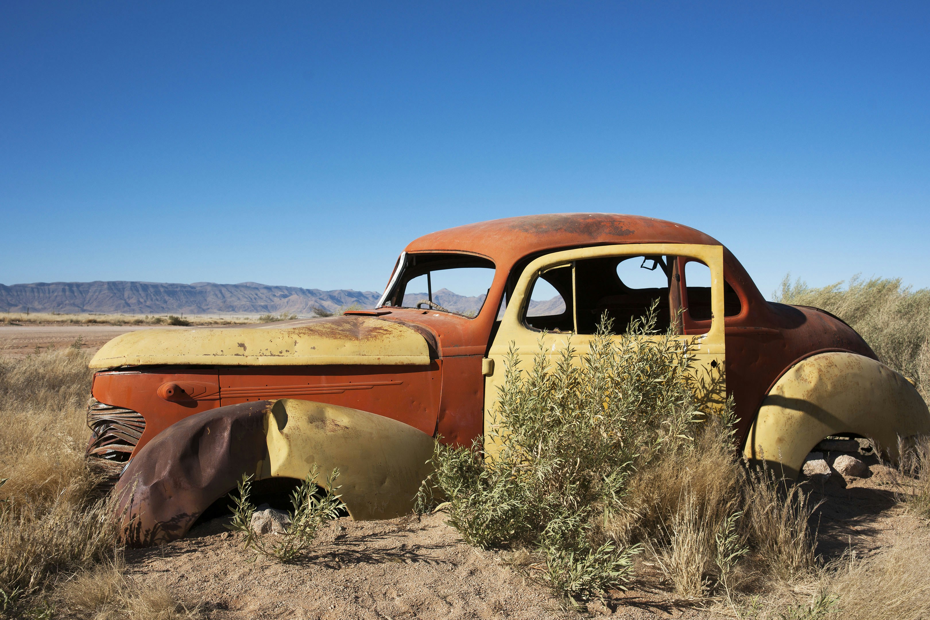 SONY DSC | An old rusty car abandoned in a desert landscape.