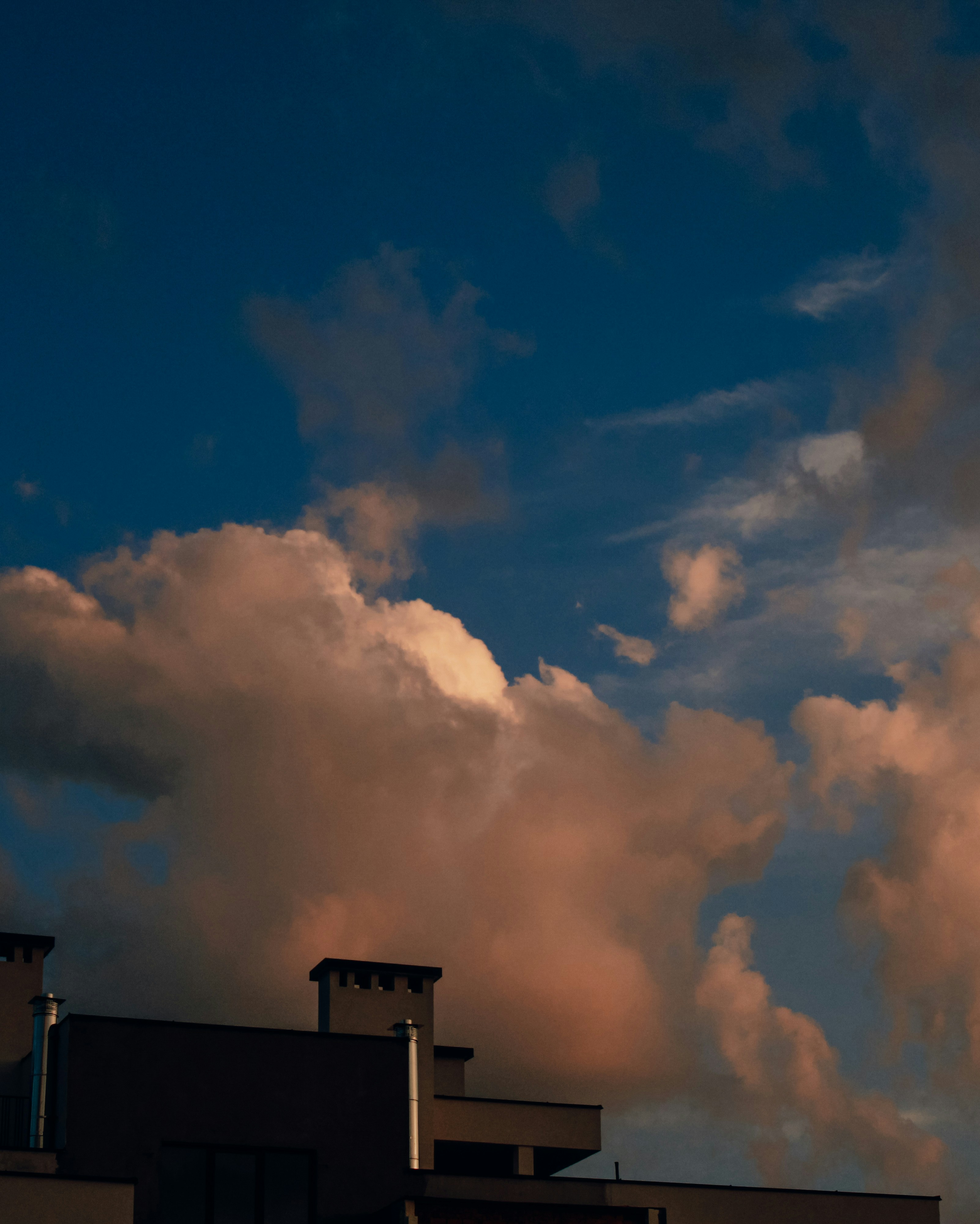 Dramatic clouds hover over building rooftops at sunset.