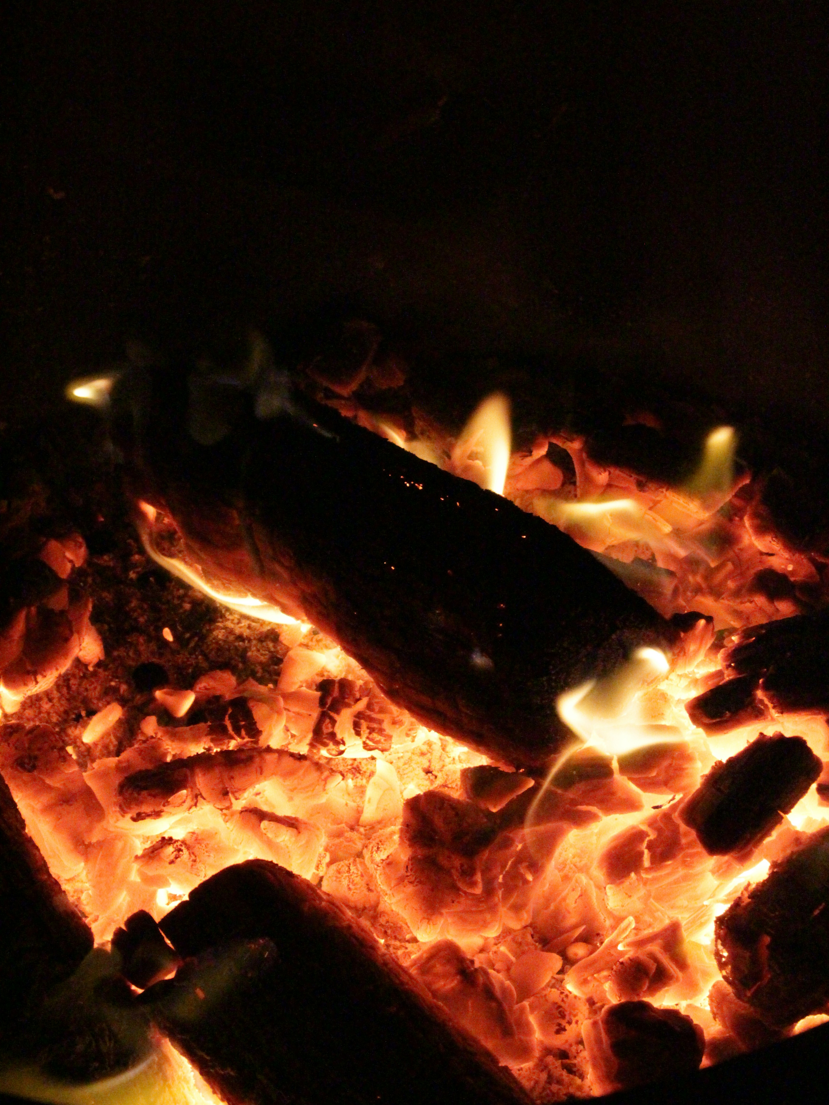Glowing embers and burning wood in a fire.