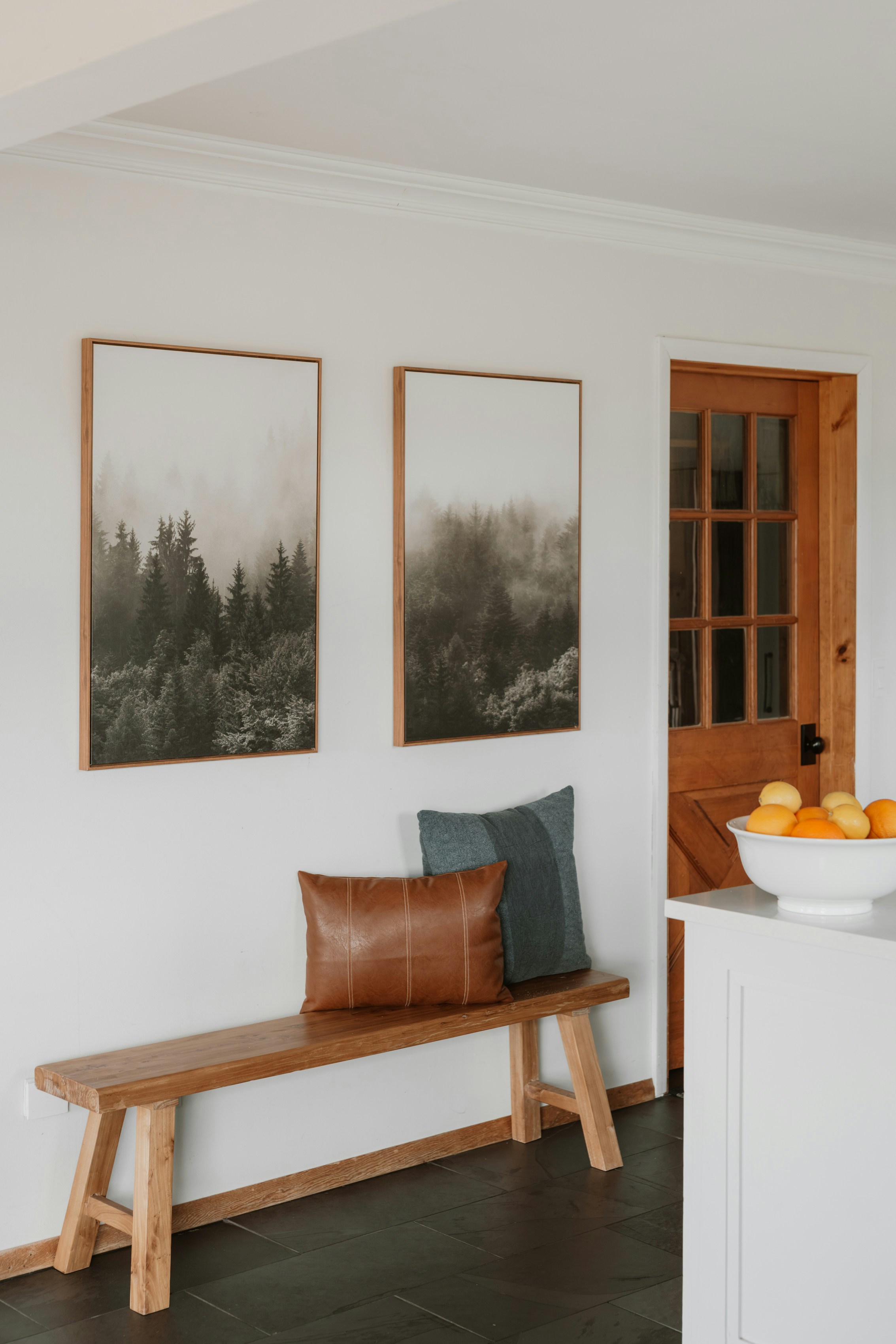 Entryway (IG: @clay.banks) | Wooden bench with pillows below forest artwork.