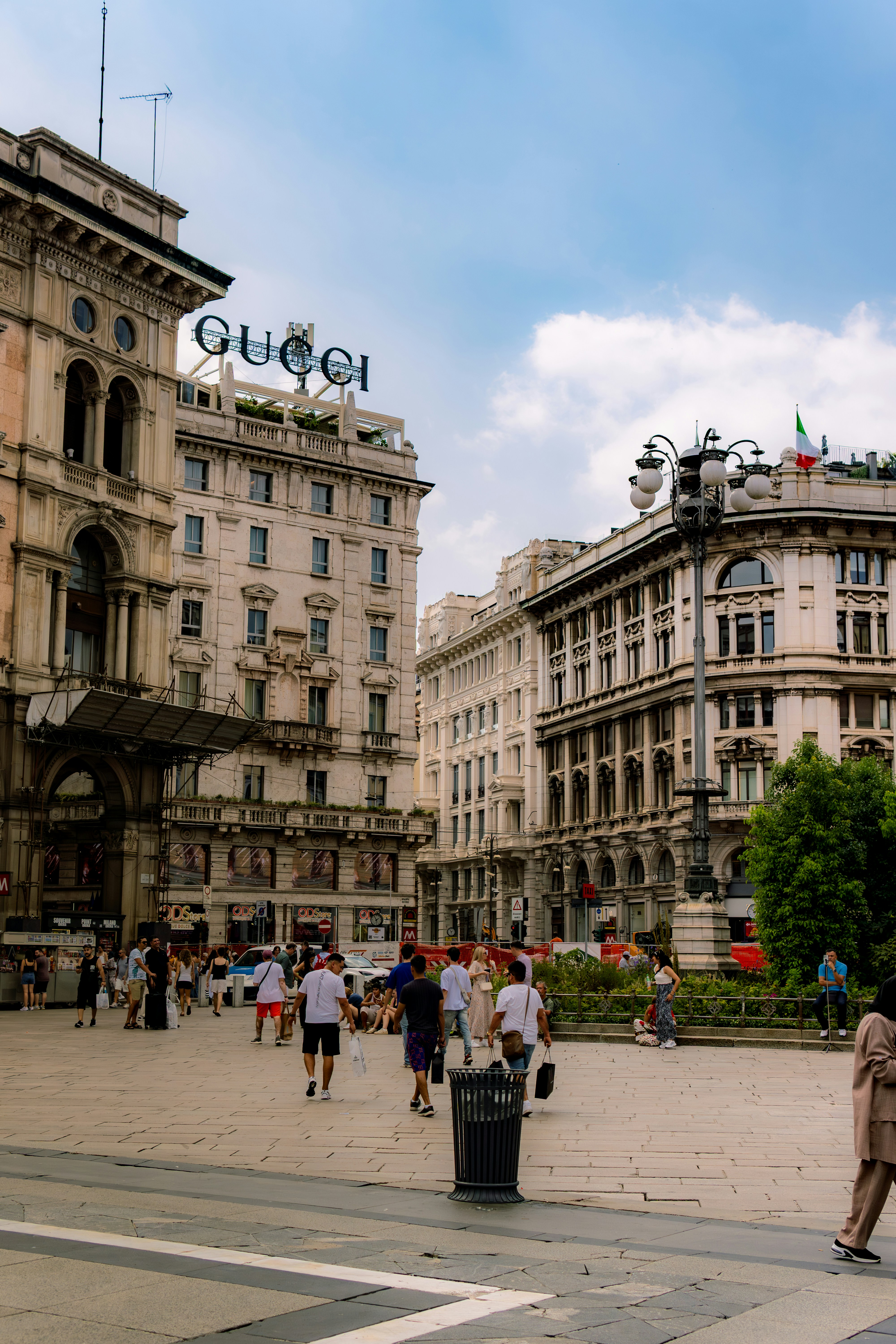 Milan | People walking in a european city square with gucci store.