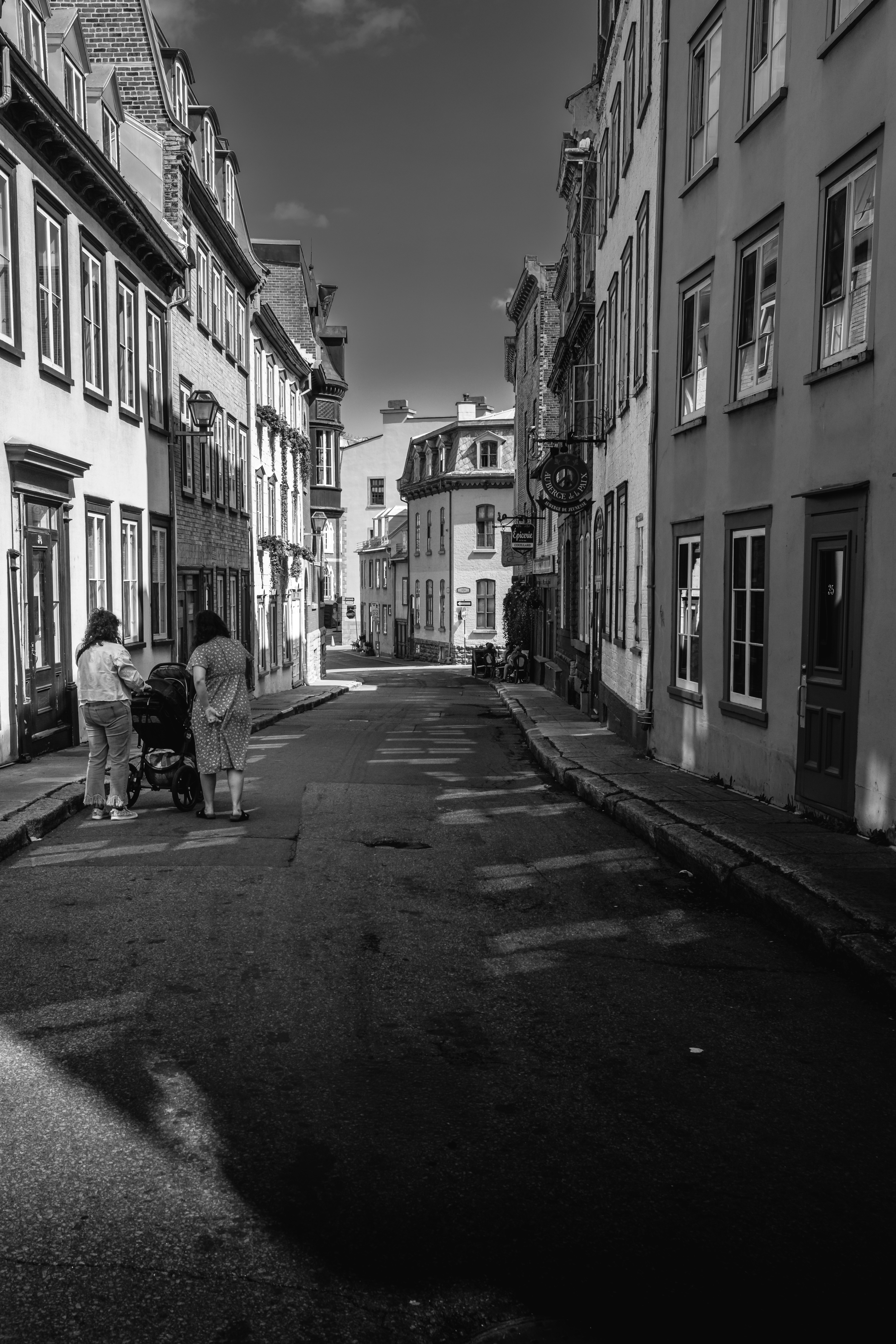 Sans titre - Untitled | Two people push a stroller down a cobblestone street.