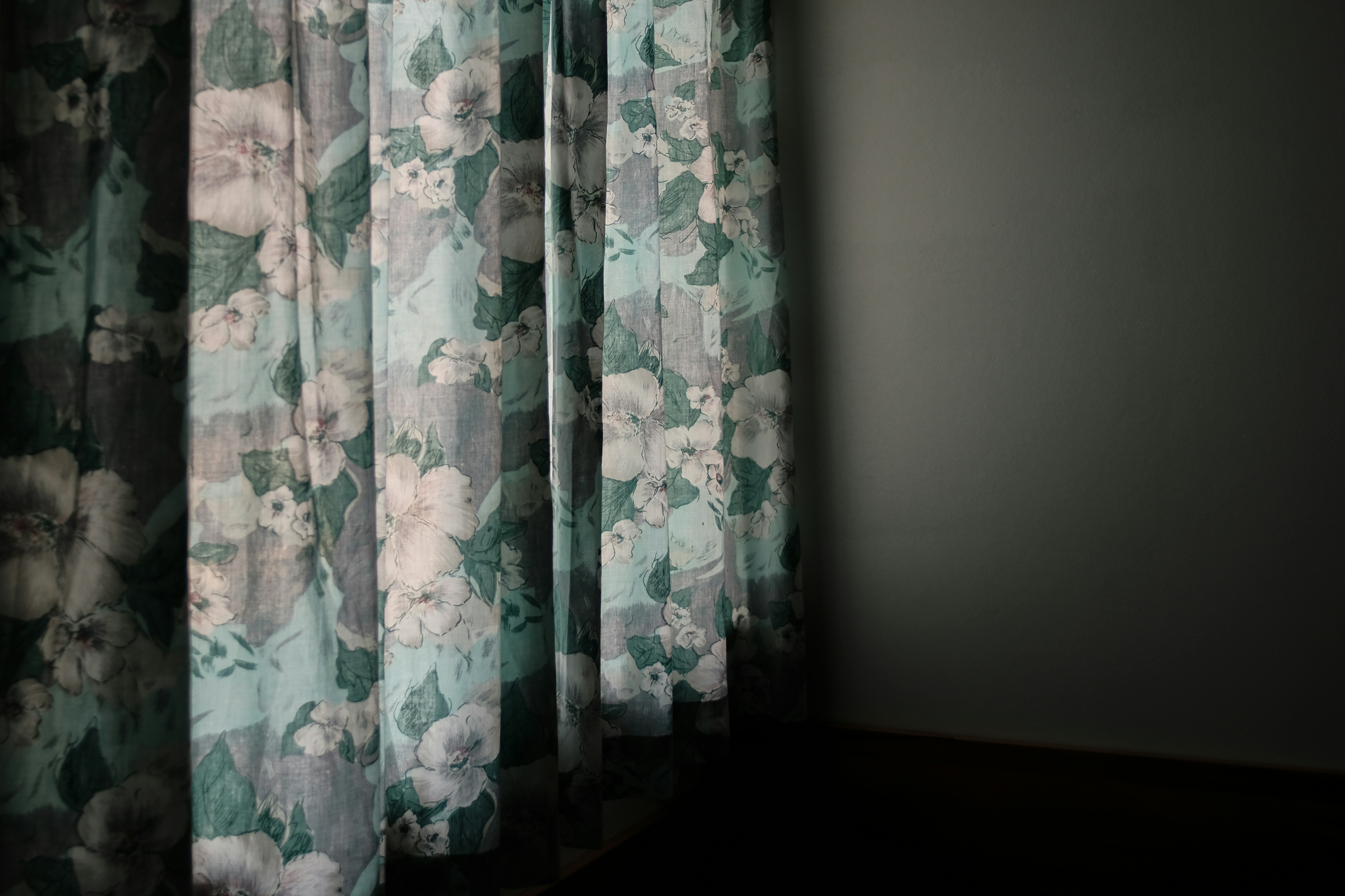 Floral curtains hang beside a plain wall.
