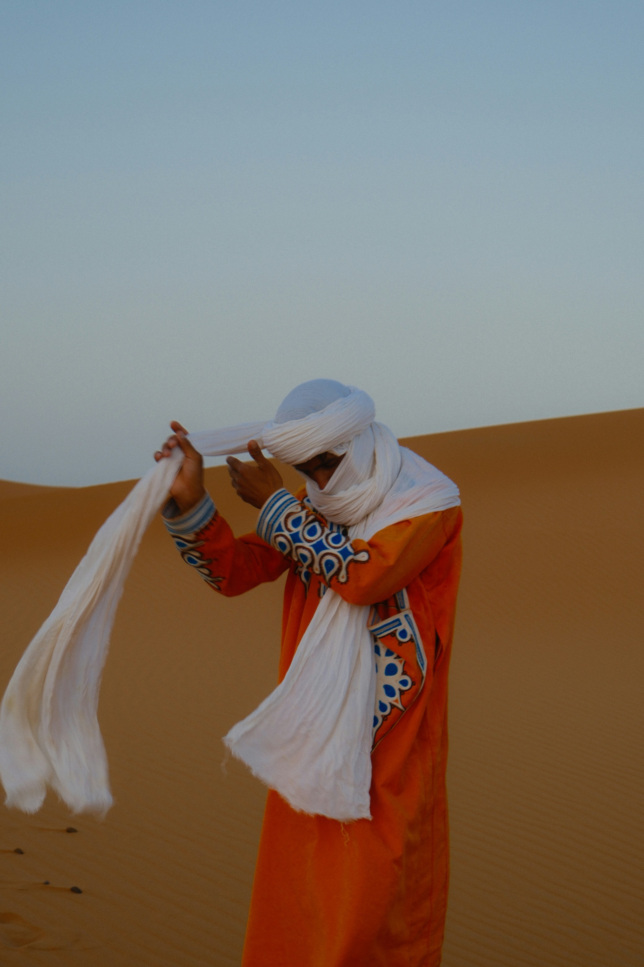 Man in traditional desert attire adjusting his turban