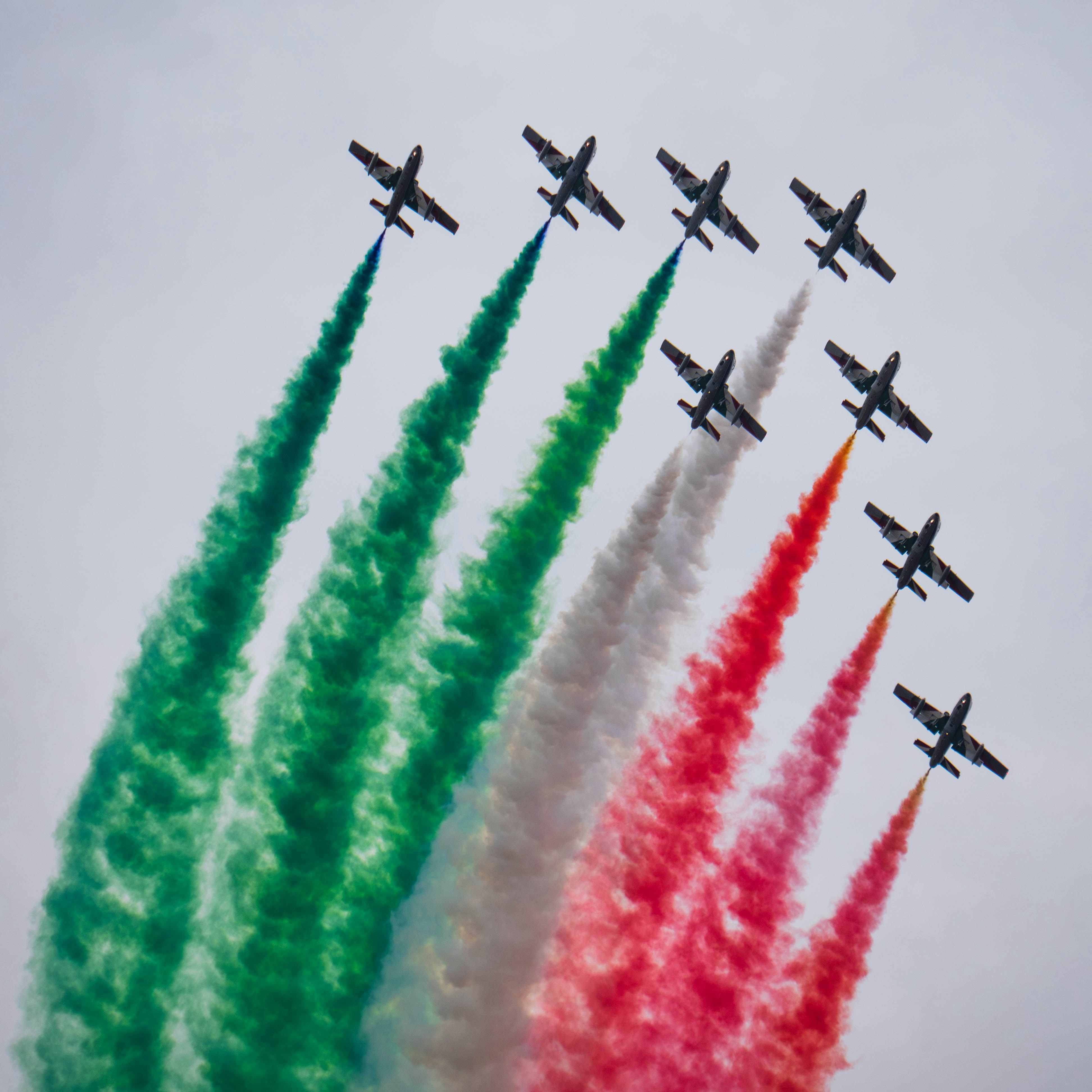 Formation of fighter jets trailing green, white, and red smoke. photo ...
