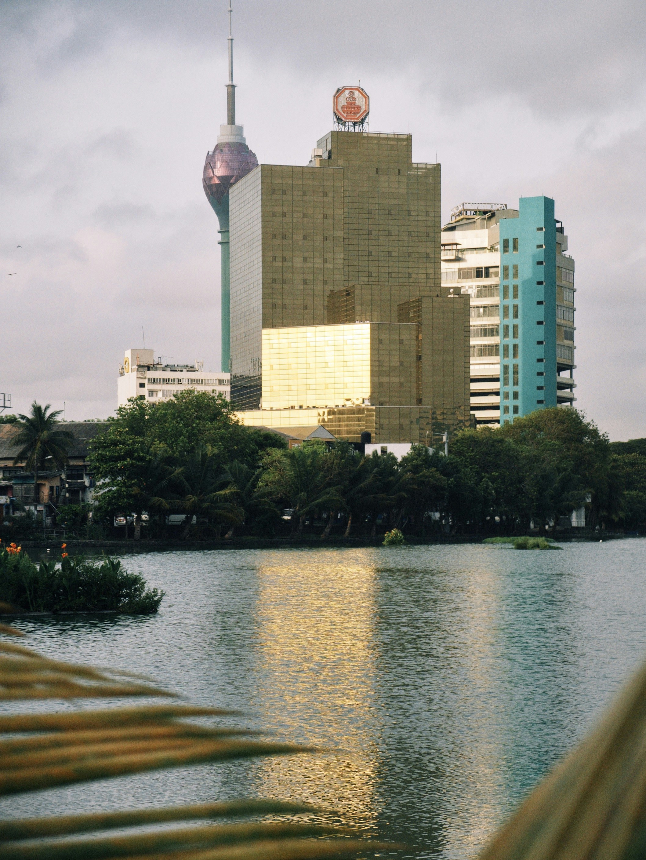 Modern city buildings reflected in a tranquil lake.