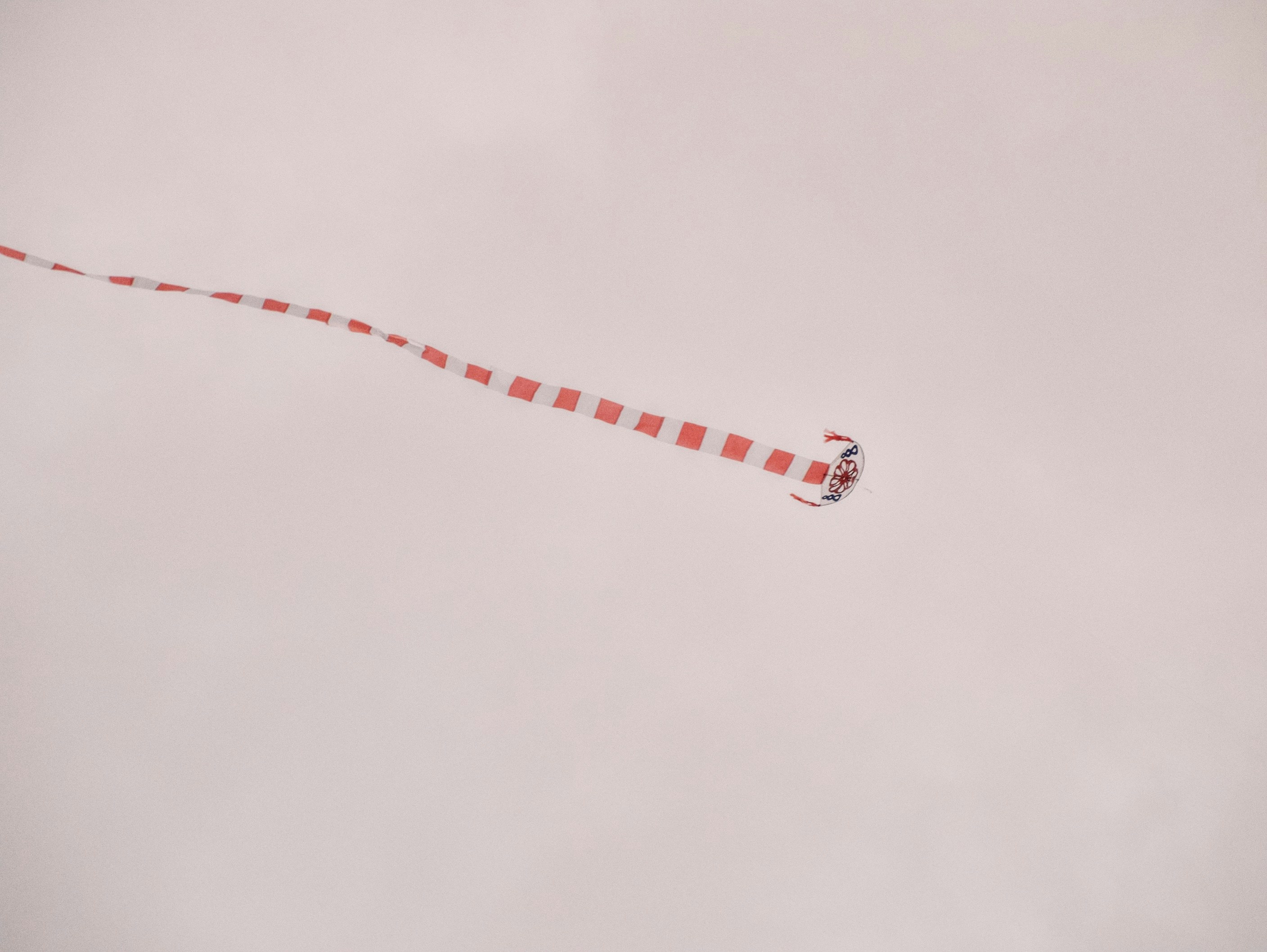 A red and white striped kite flying in the sky