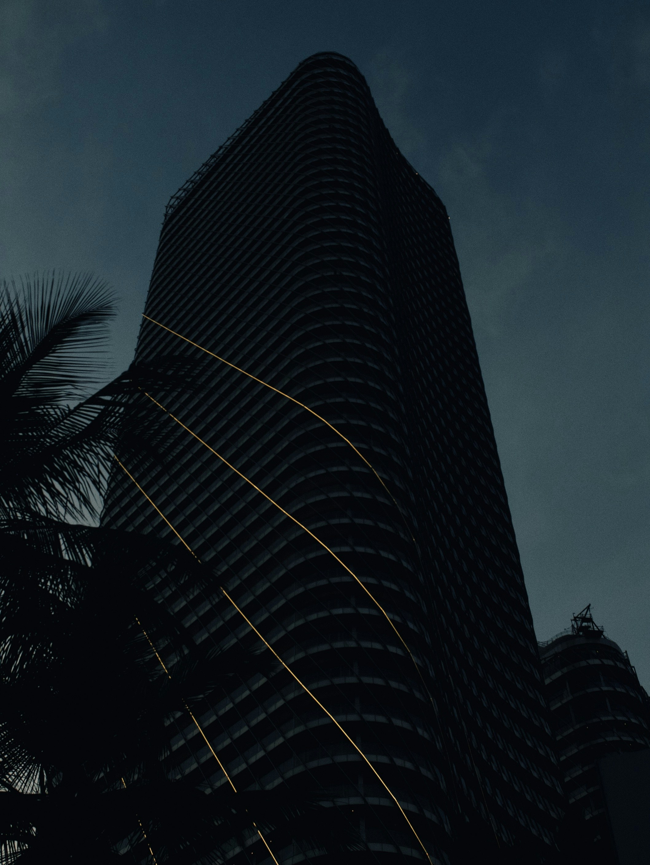 Modern skyscraper with curved facade at dusk.