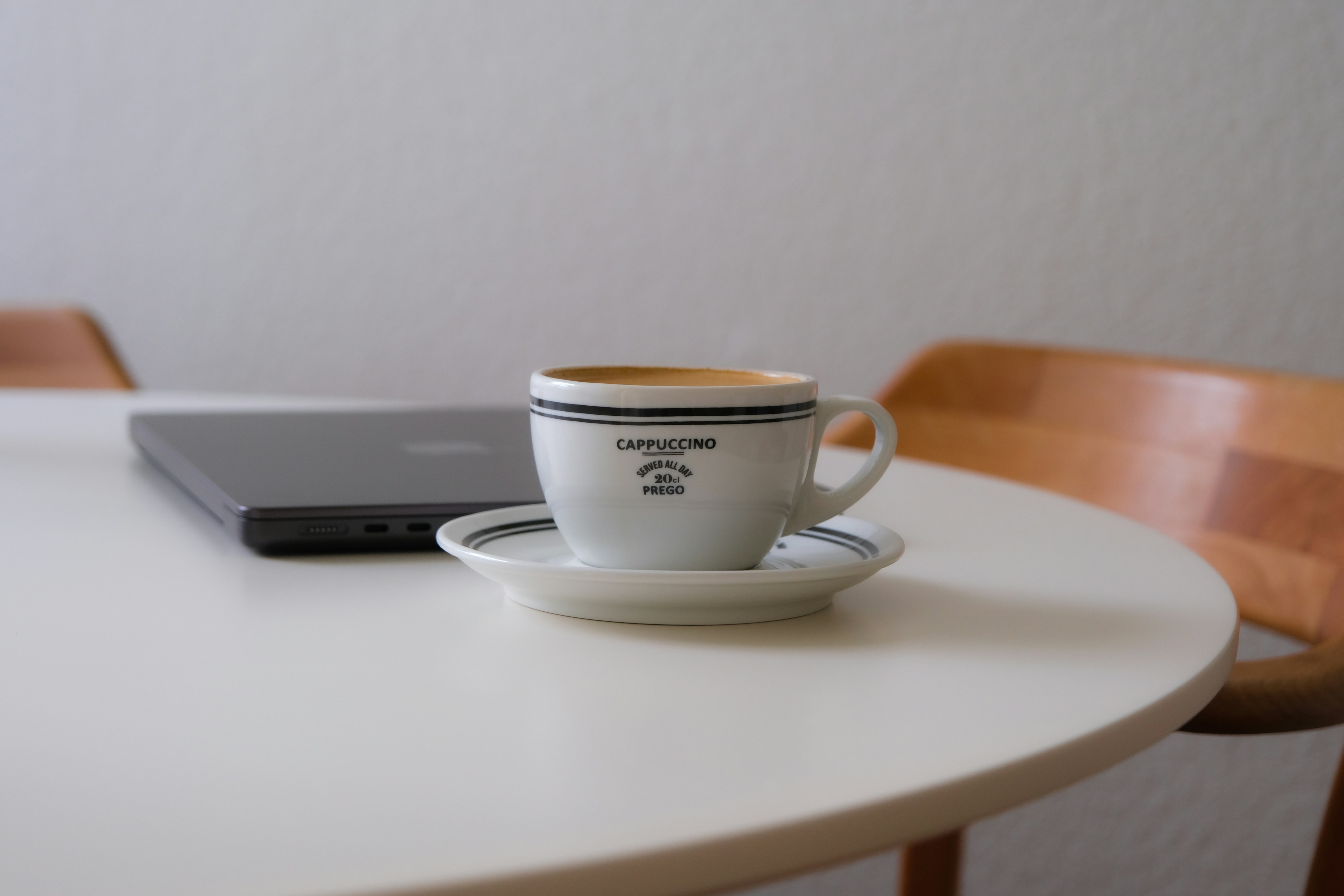 Cup of coffee and laptop on a white table
