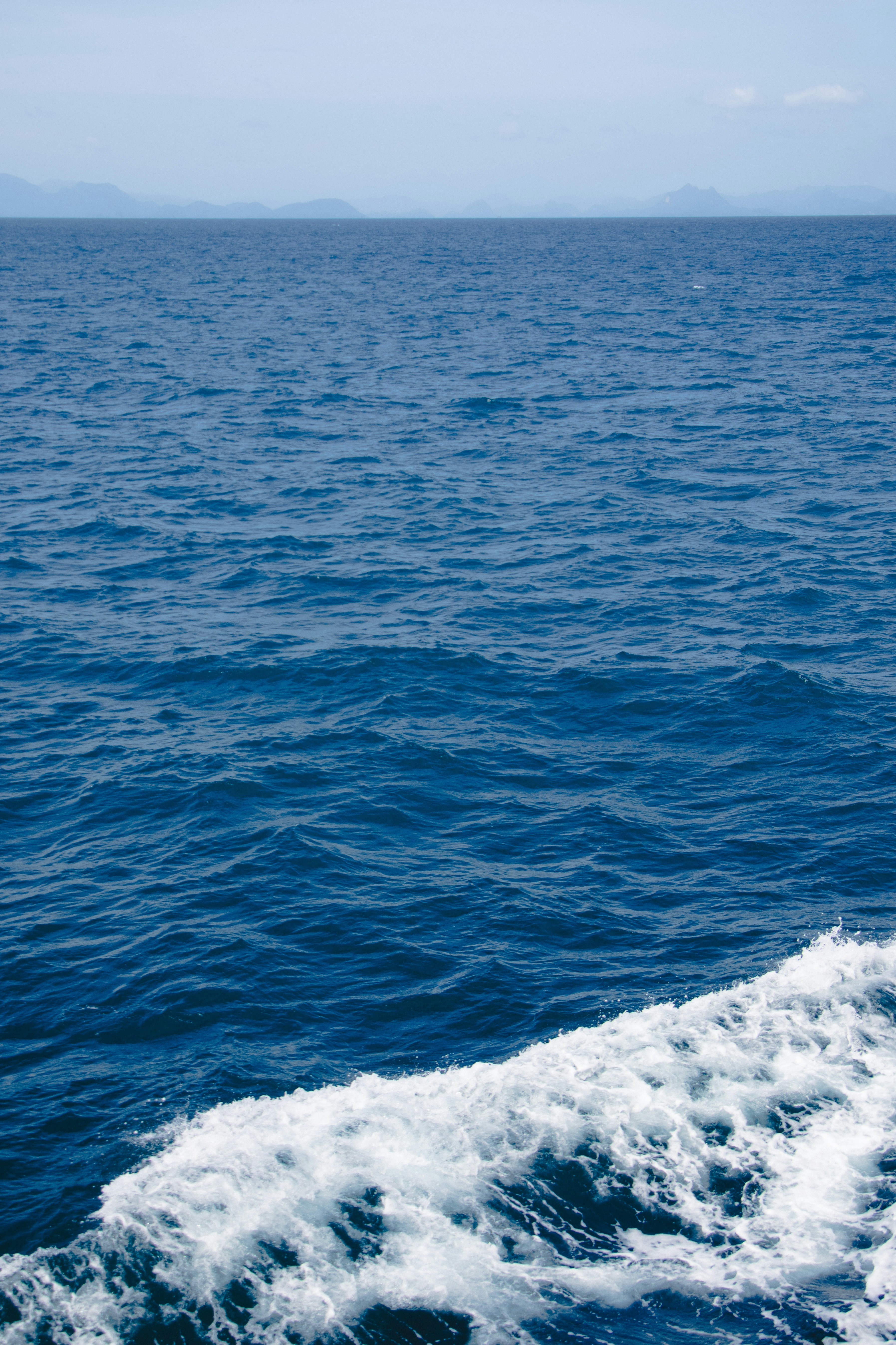 Deep blue ocean with white waves and distant islands