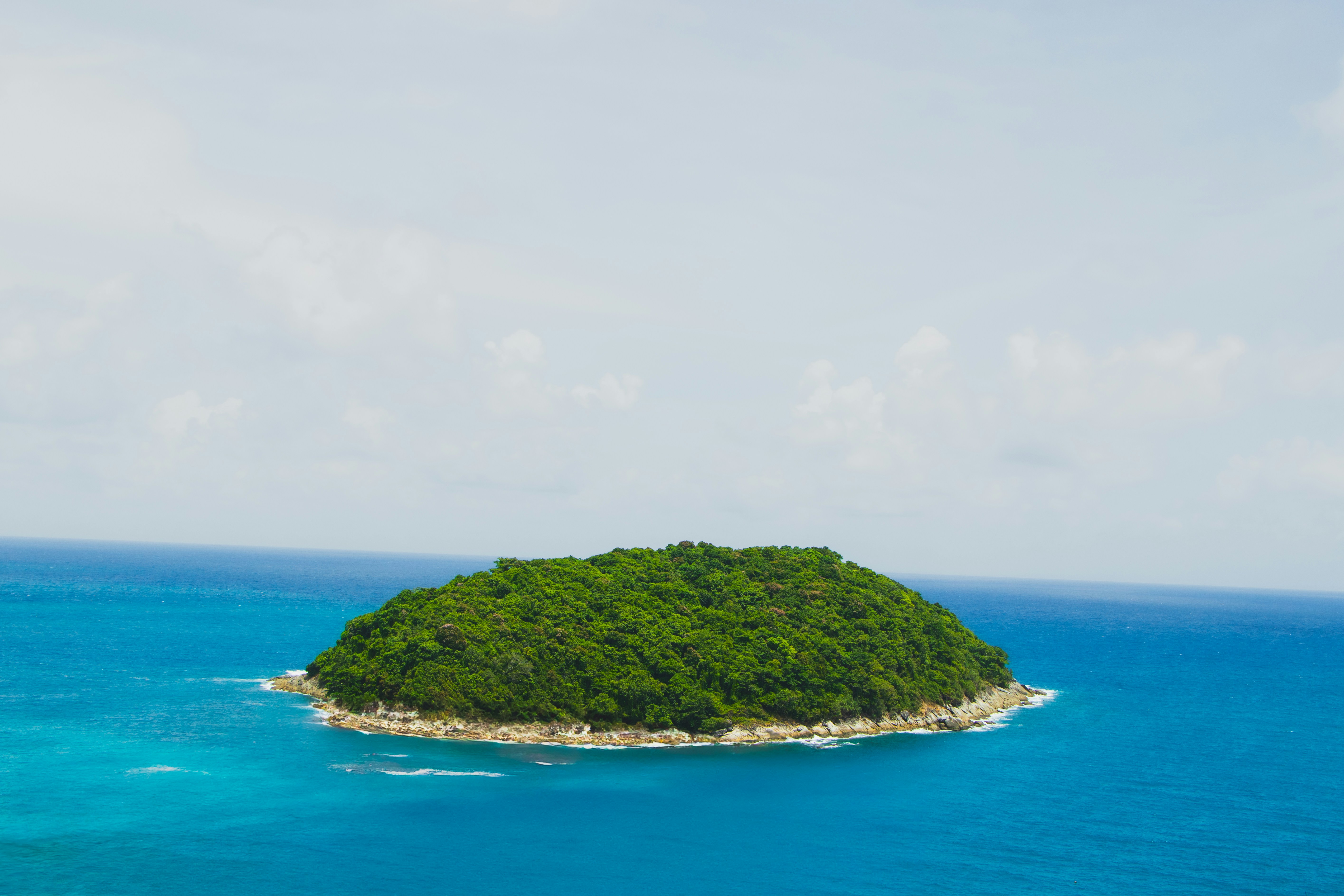 A lush green island surrounded by clear blue ocean.