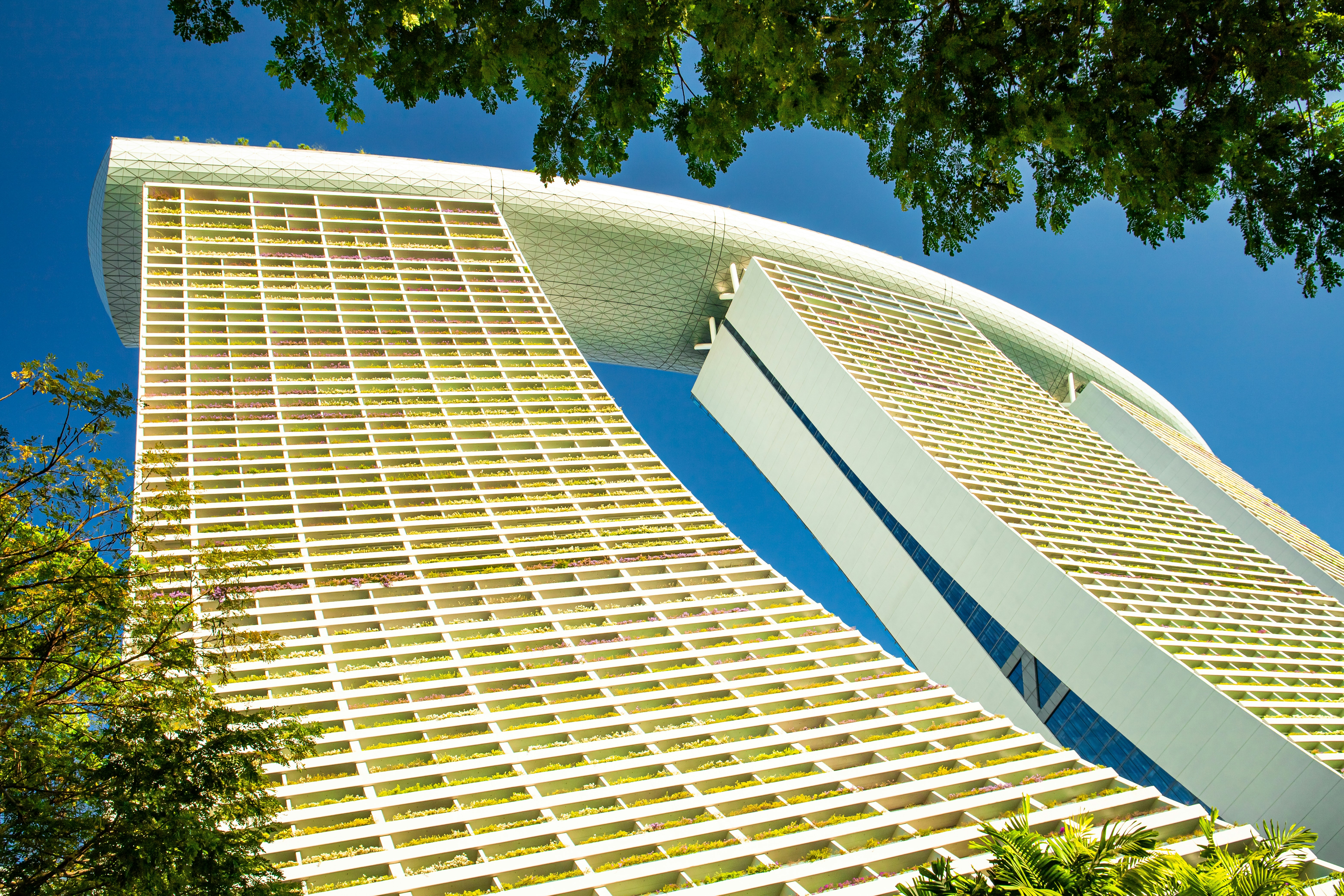 A tall building is prominently visible, set against a vivid blue sky that enhances the urban landscape | Modern hotel with unique architecture under blue sky