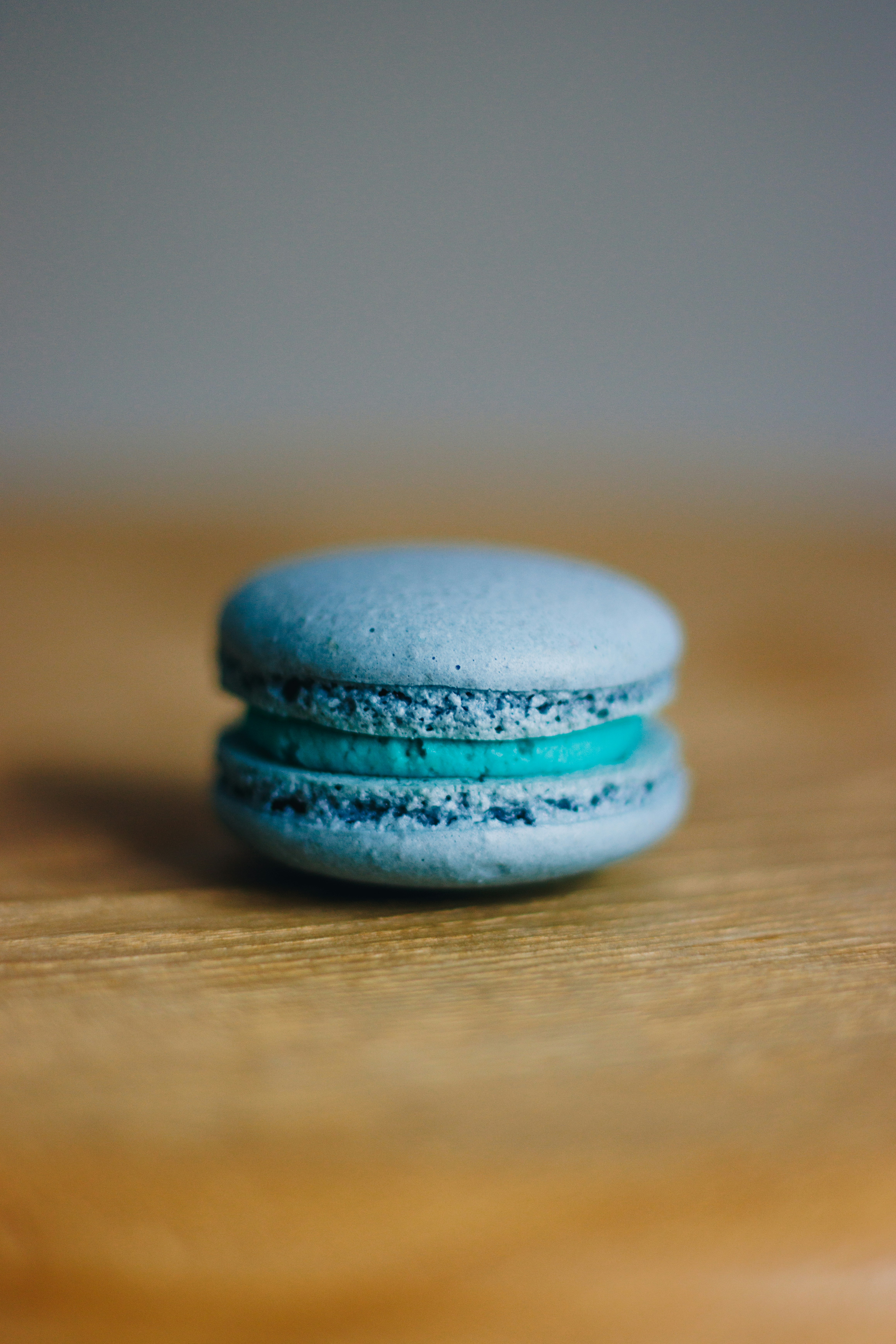 A single blue macaron on a wooden surface. photo – Free Image on Unsplash