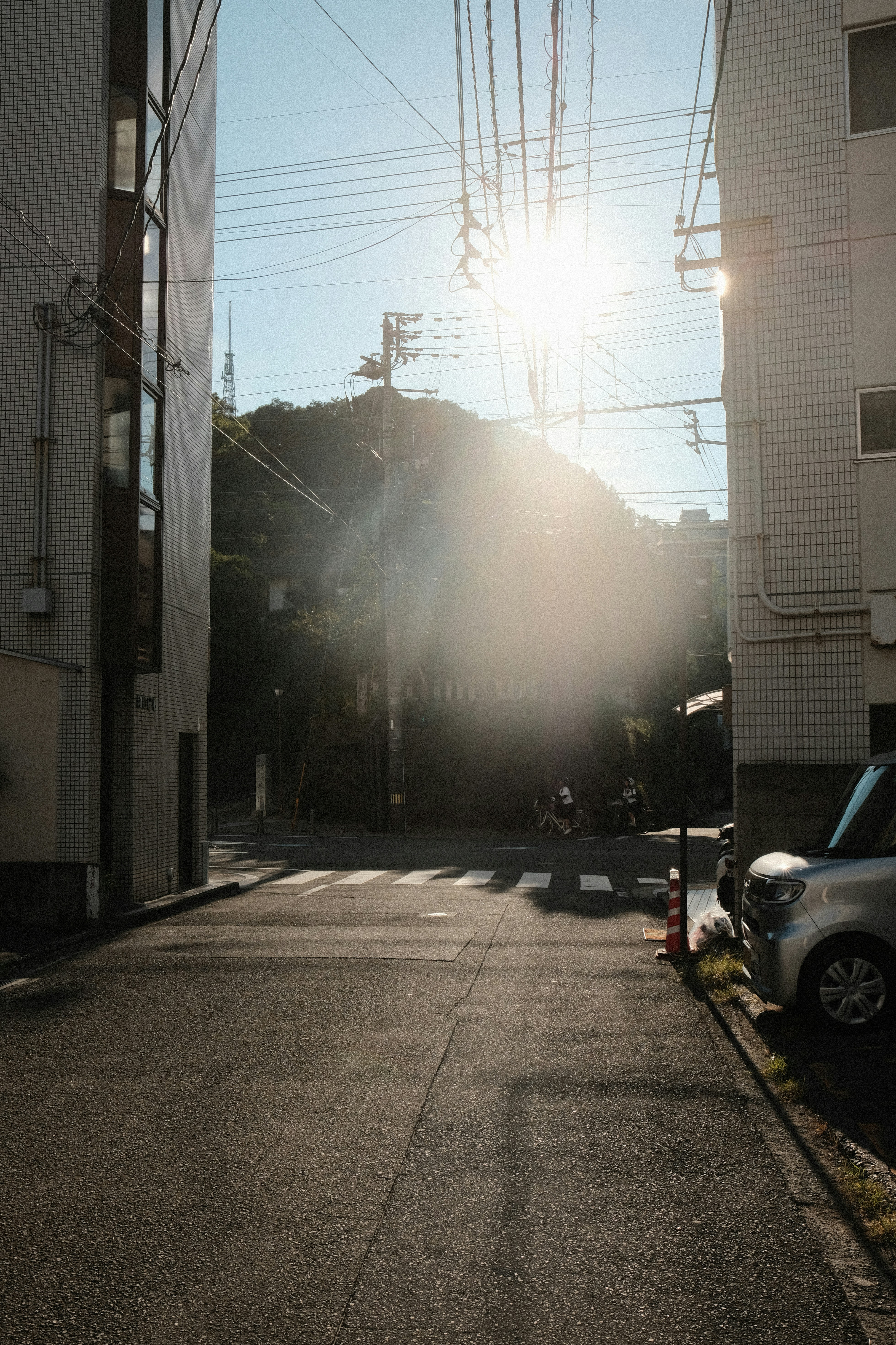 Sunlight streams down a narrow street between buildings.