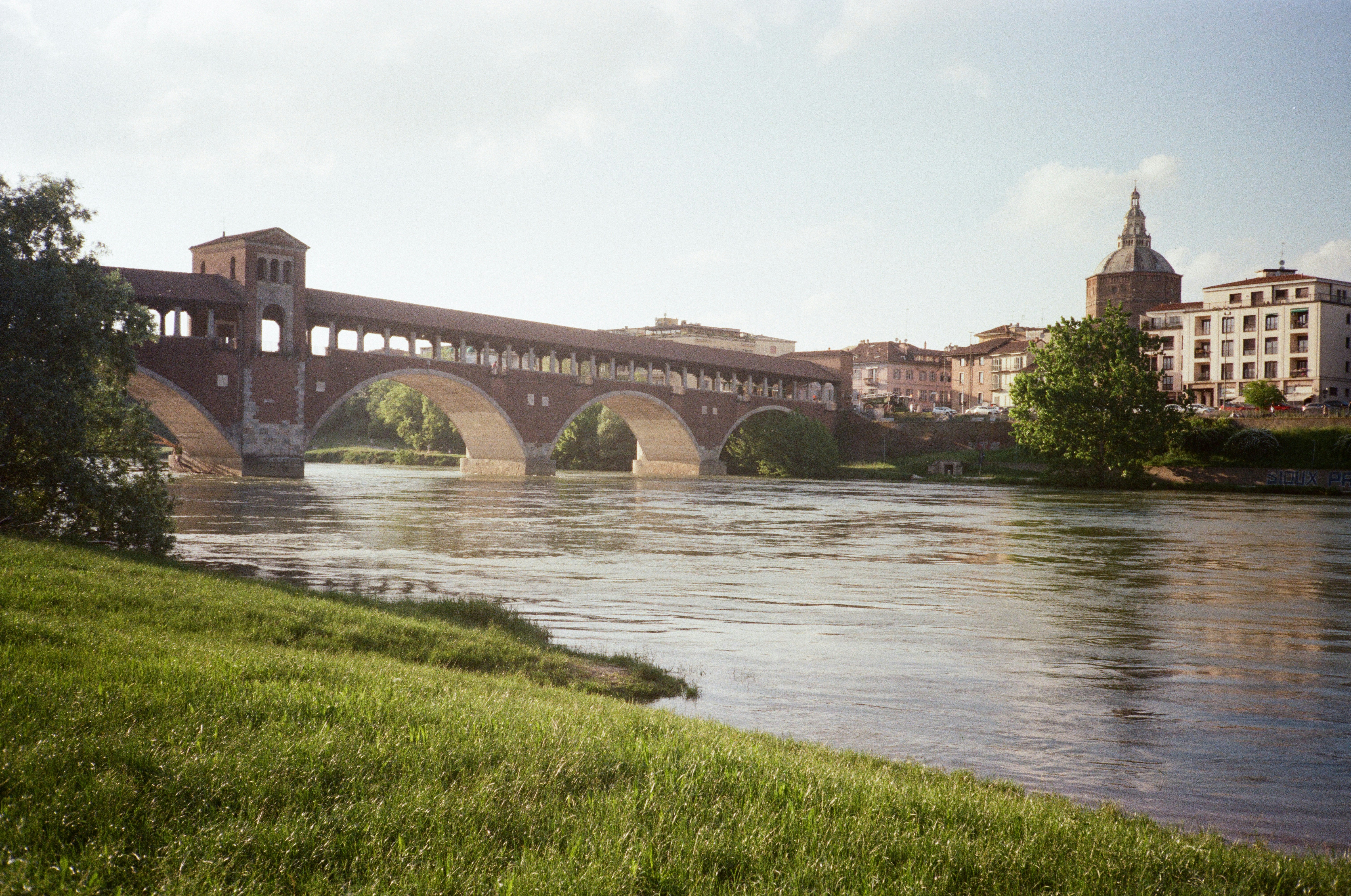 Covered bridge over a wide river with buildings beyond