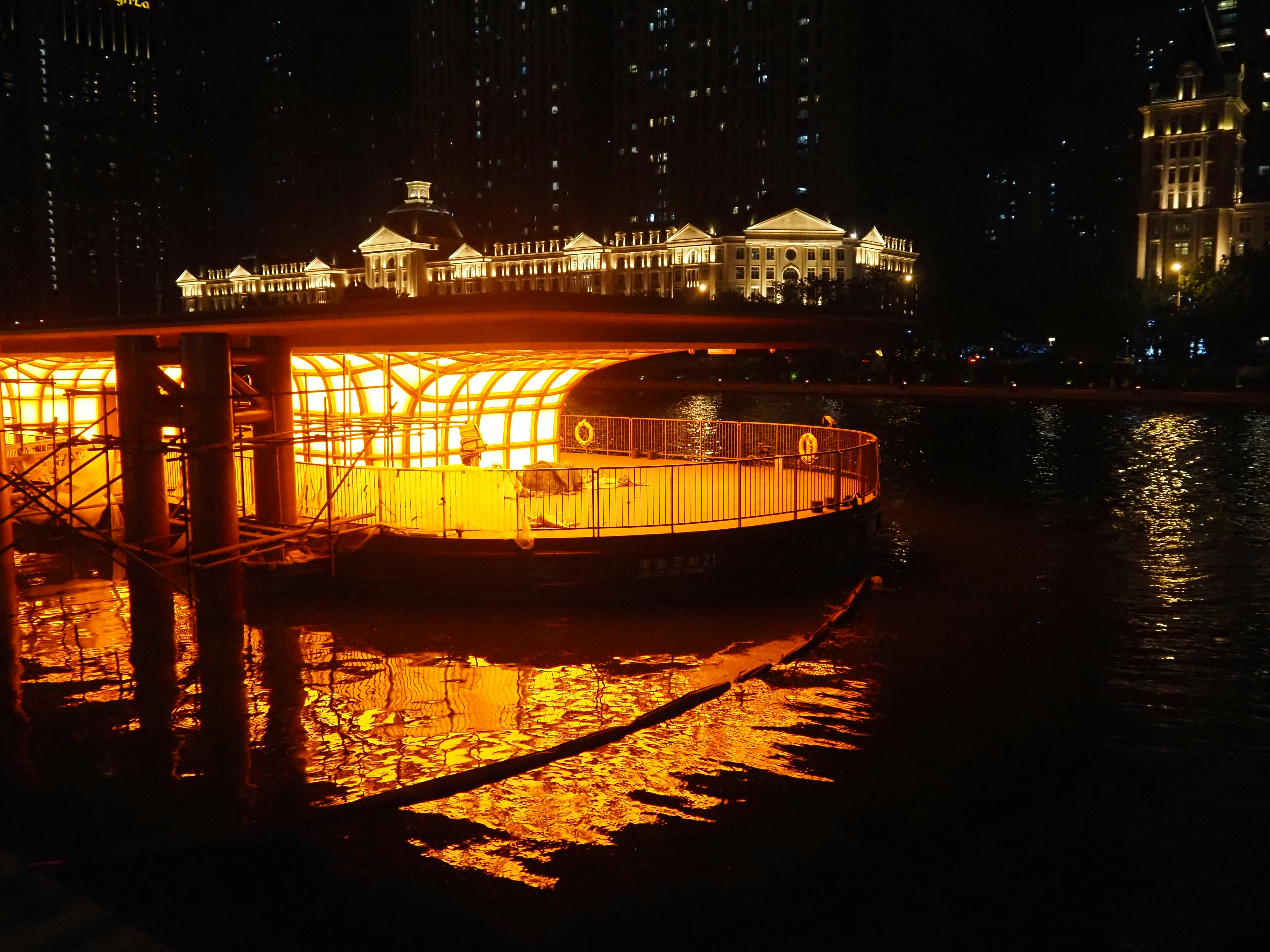 Illuminated bridge and boat on river at night