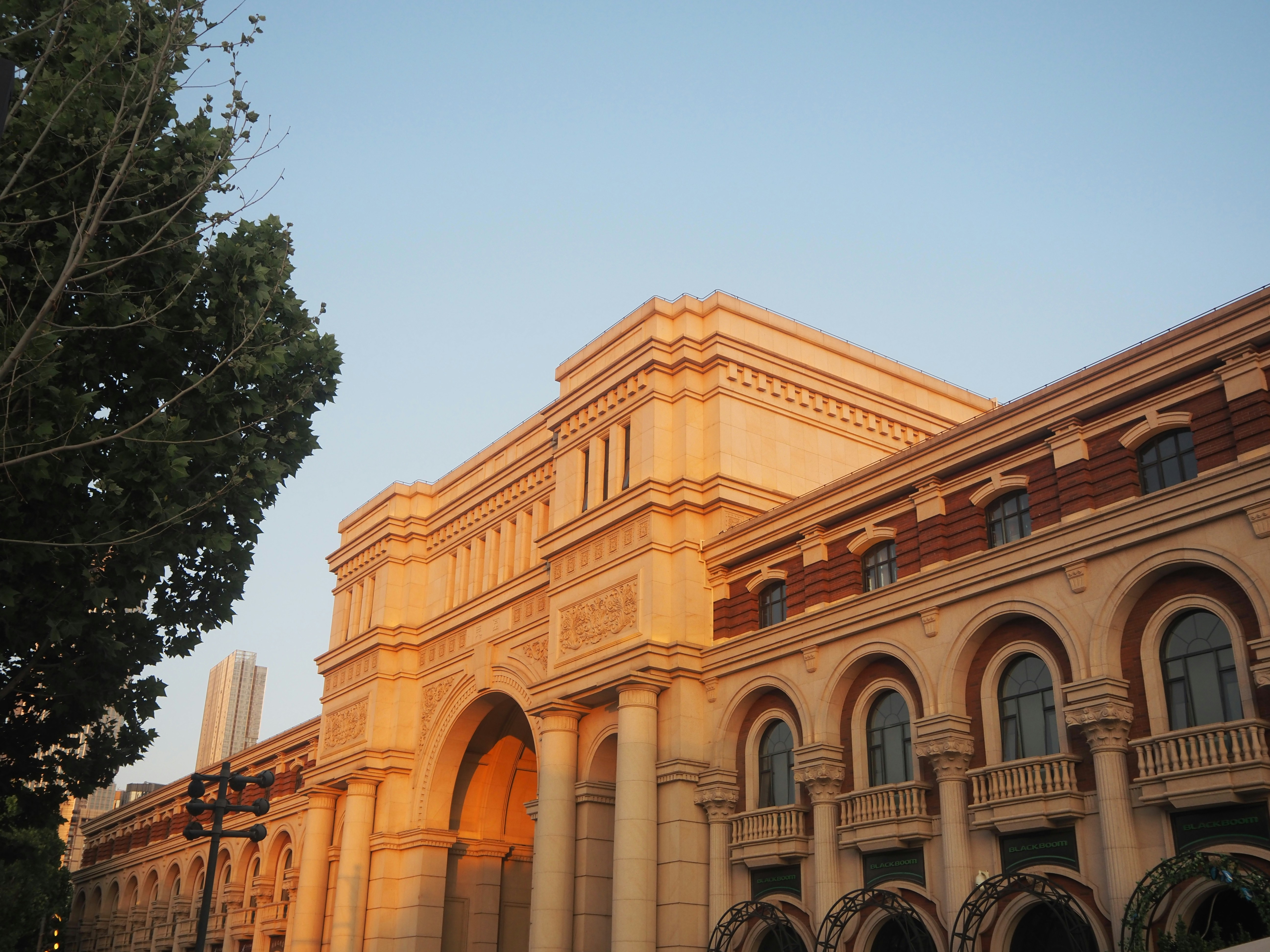 Grand building with arched windows and columns at sunset.