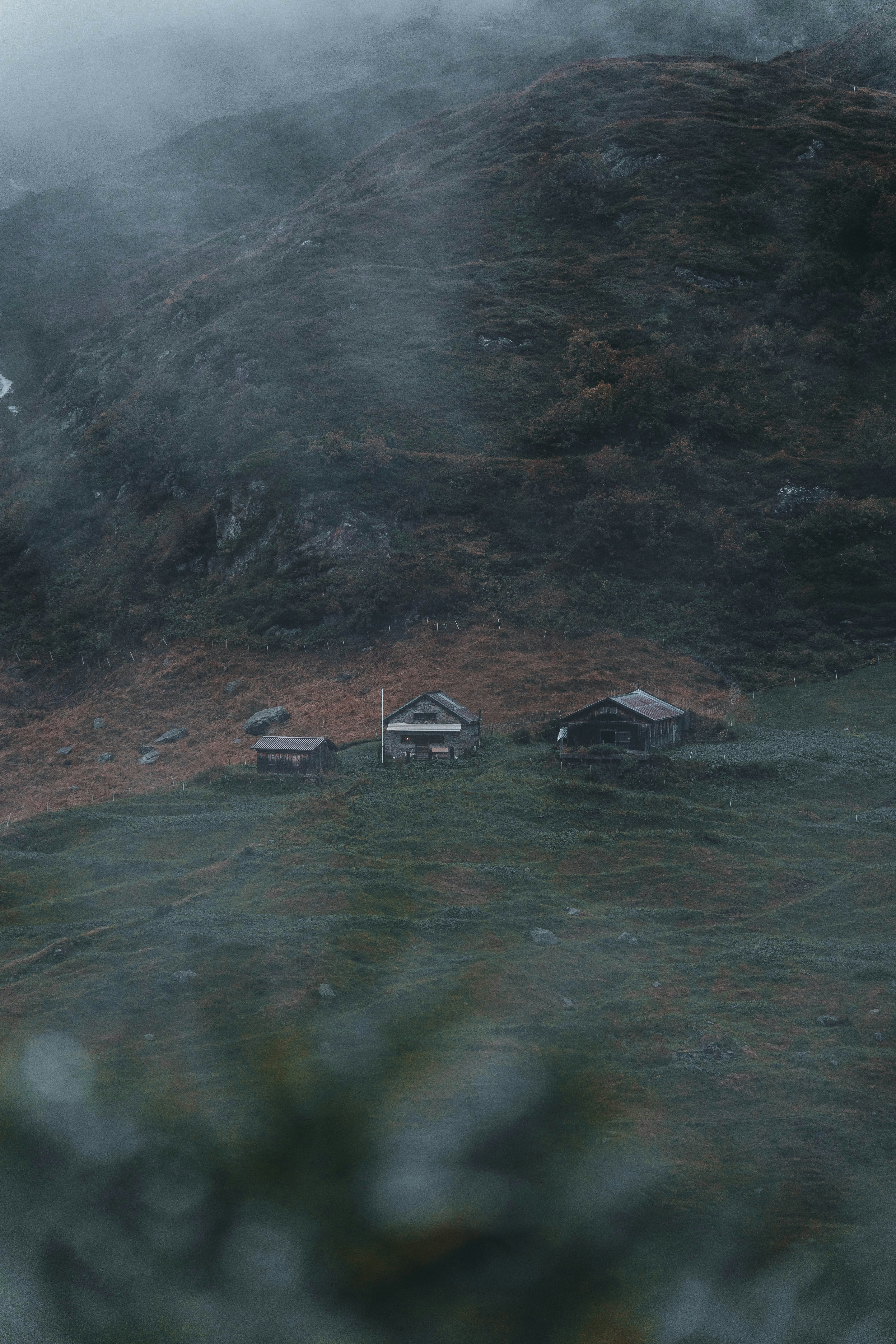 Three rustic cabins nestled on a misty mountainside.
