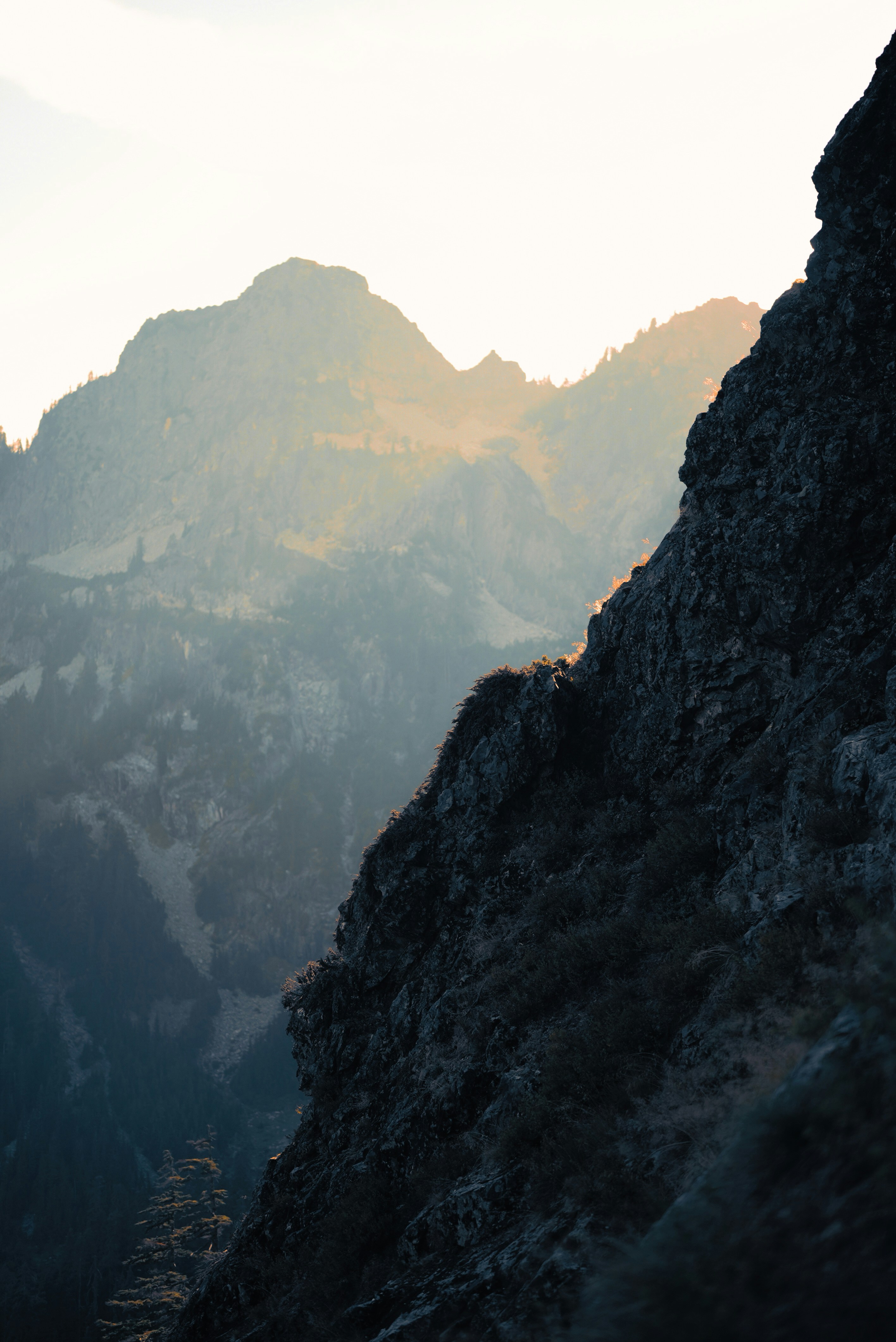 Sunlight illuminates distant mountain peaks behind a rocky foreground.