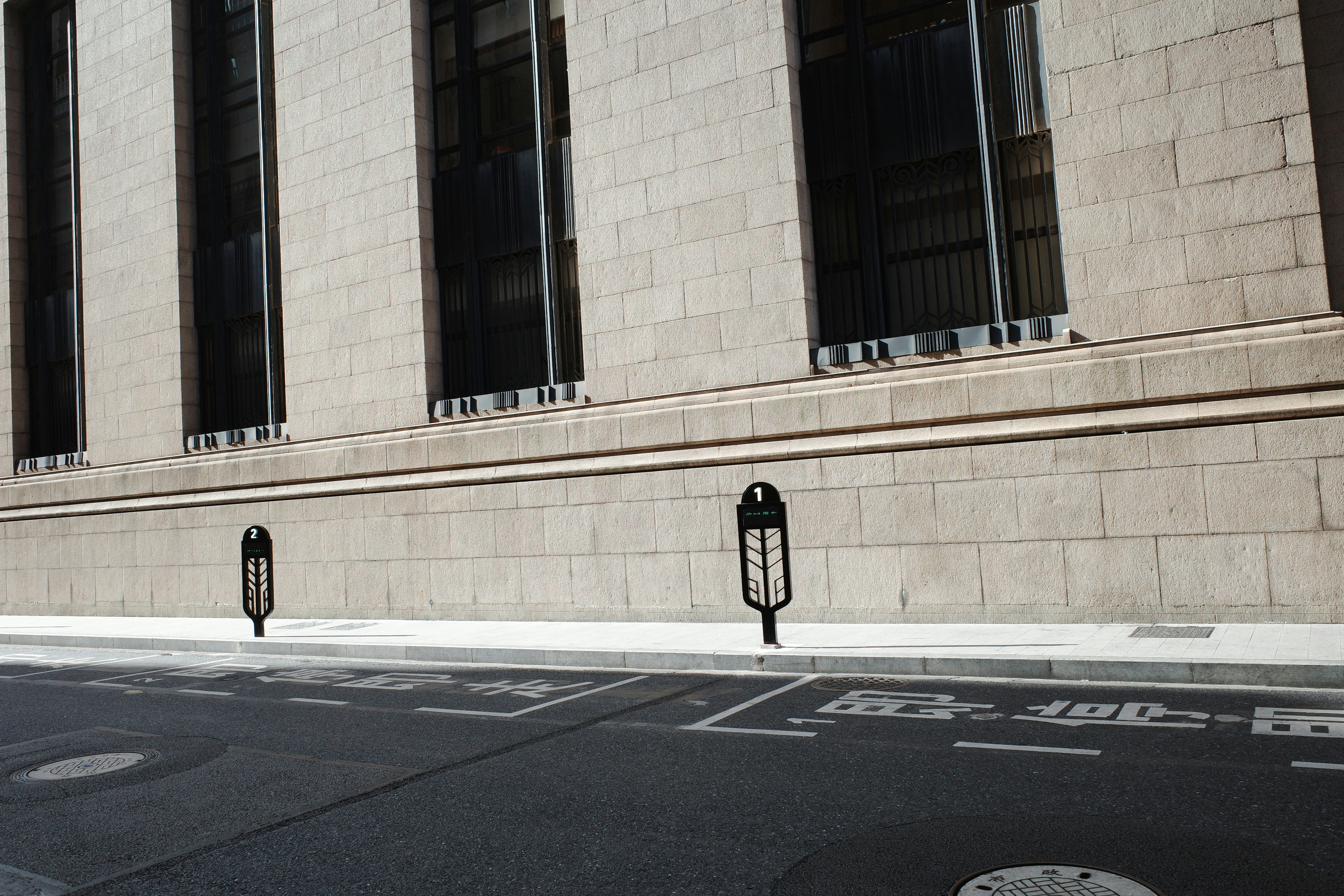 Modern building facade with street and two trash cans.