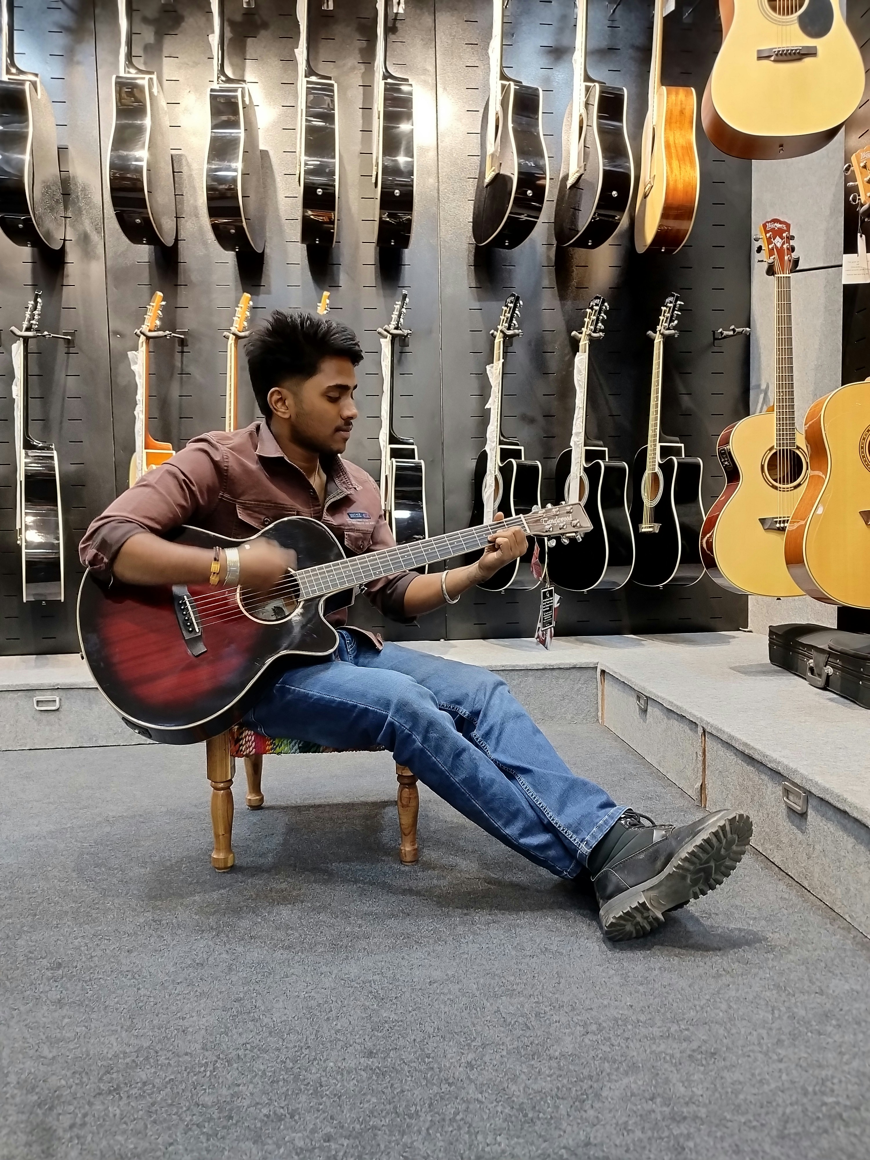 suhavi mart store | Young man playing an acoustic guitar in a shop.