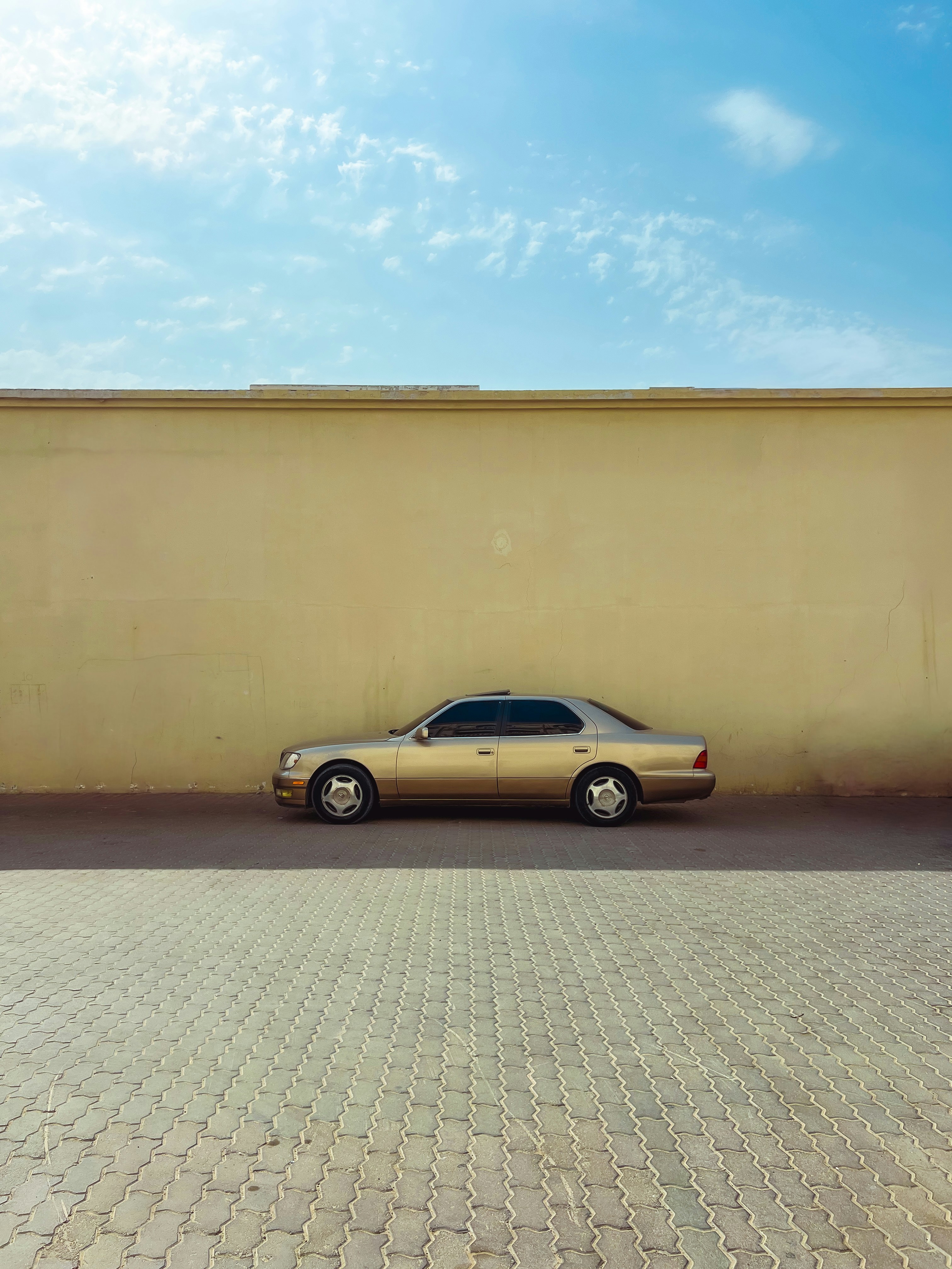 LS400 | Gold sedan parked against a yellow wall.