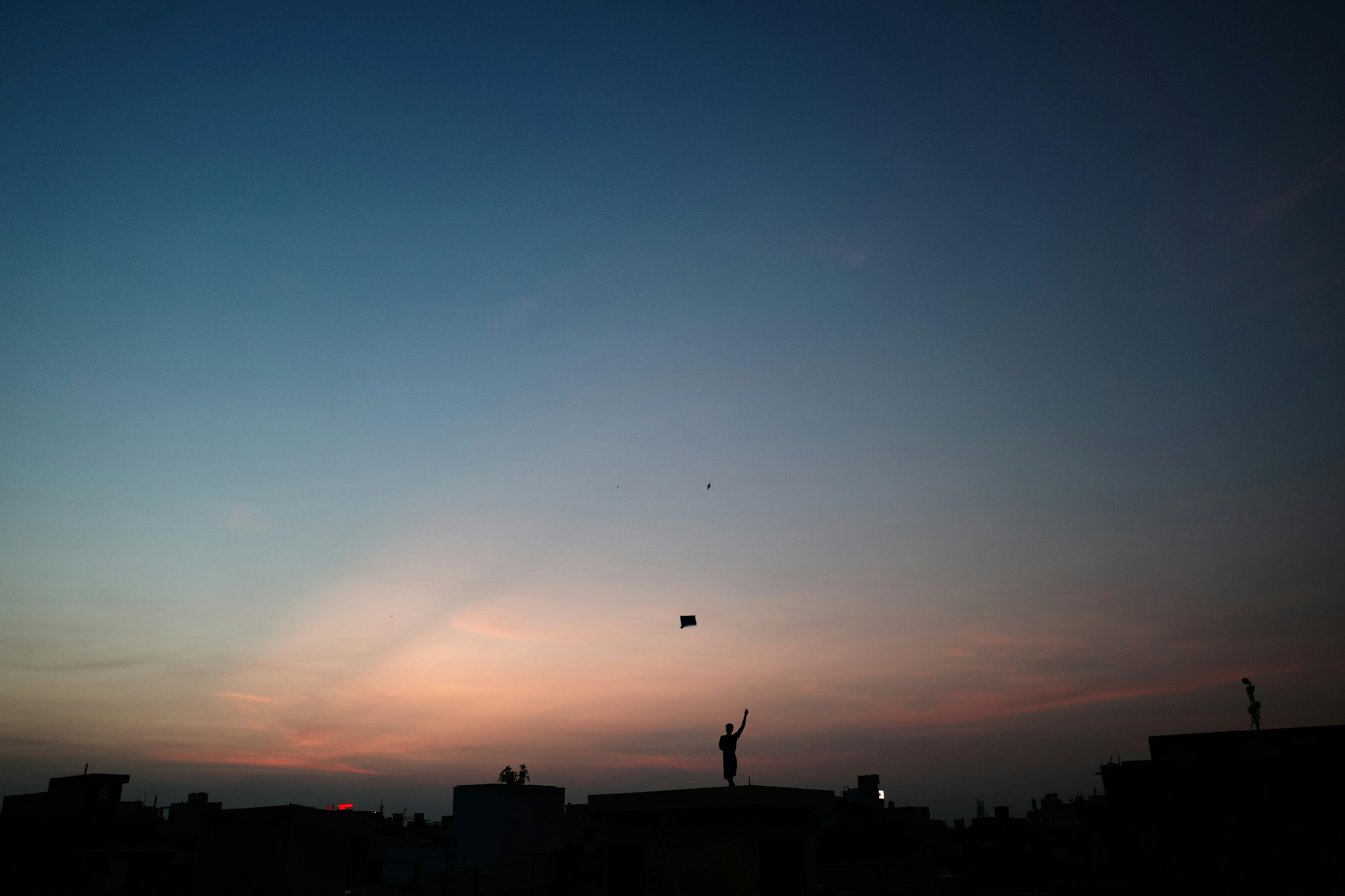 Silhouettes of people flying a kite at sunset