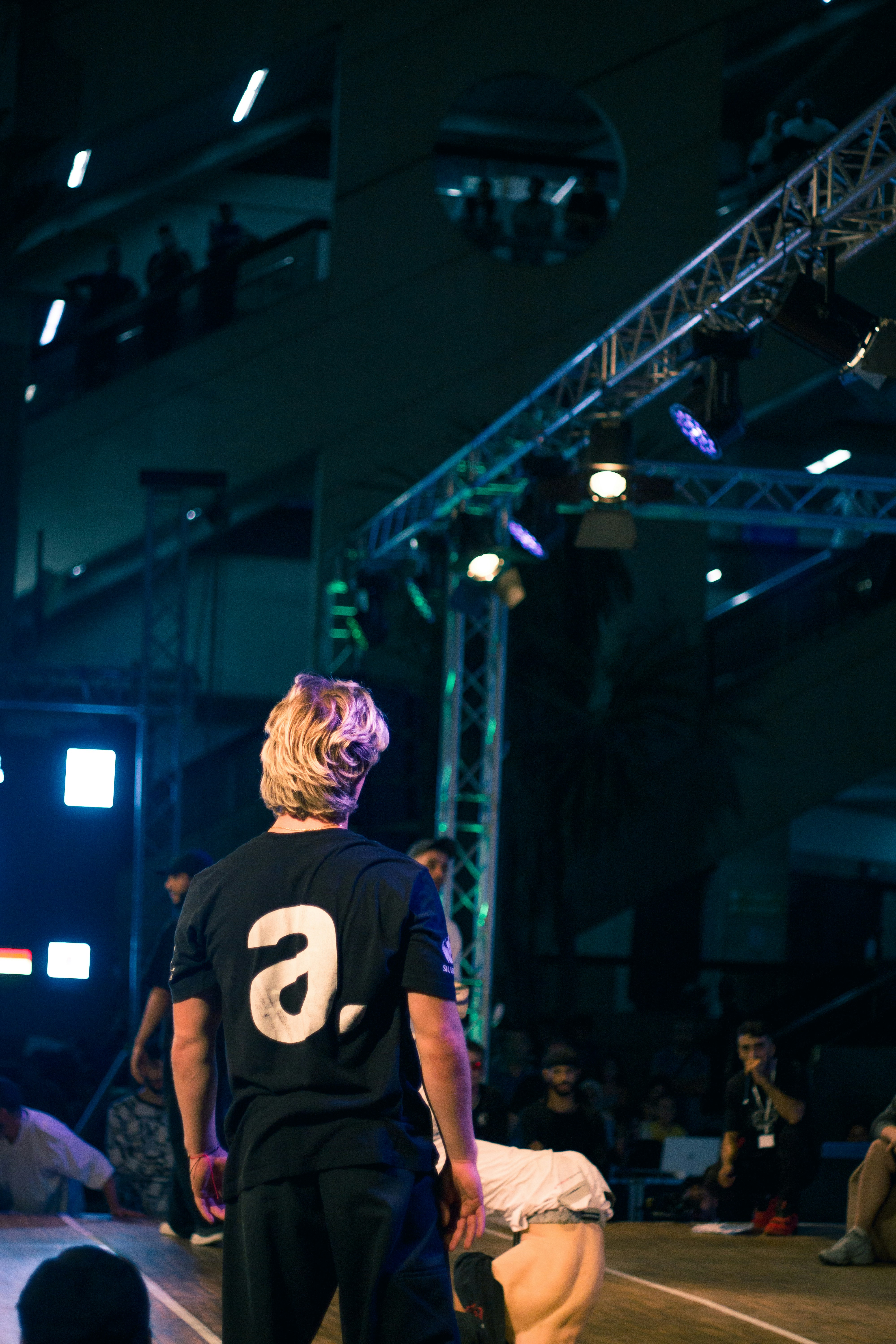 Backstage Spotlight: A Performer in Focus Beneath Neon Trusses