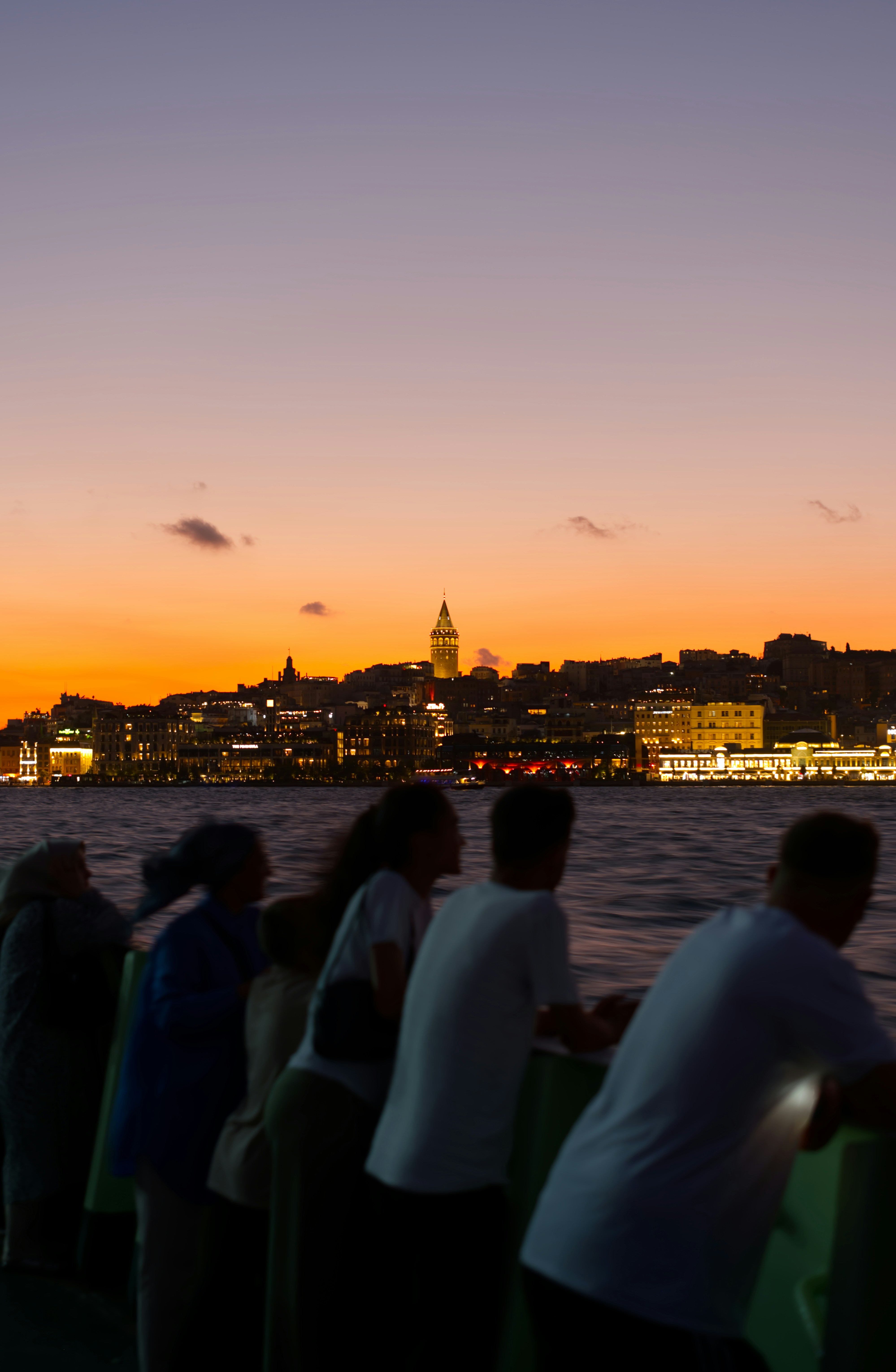 People watch city skyline at sunset from boat
