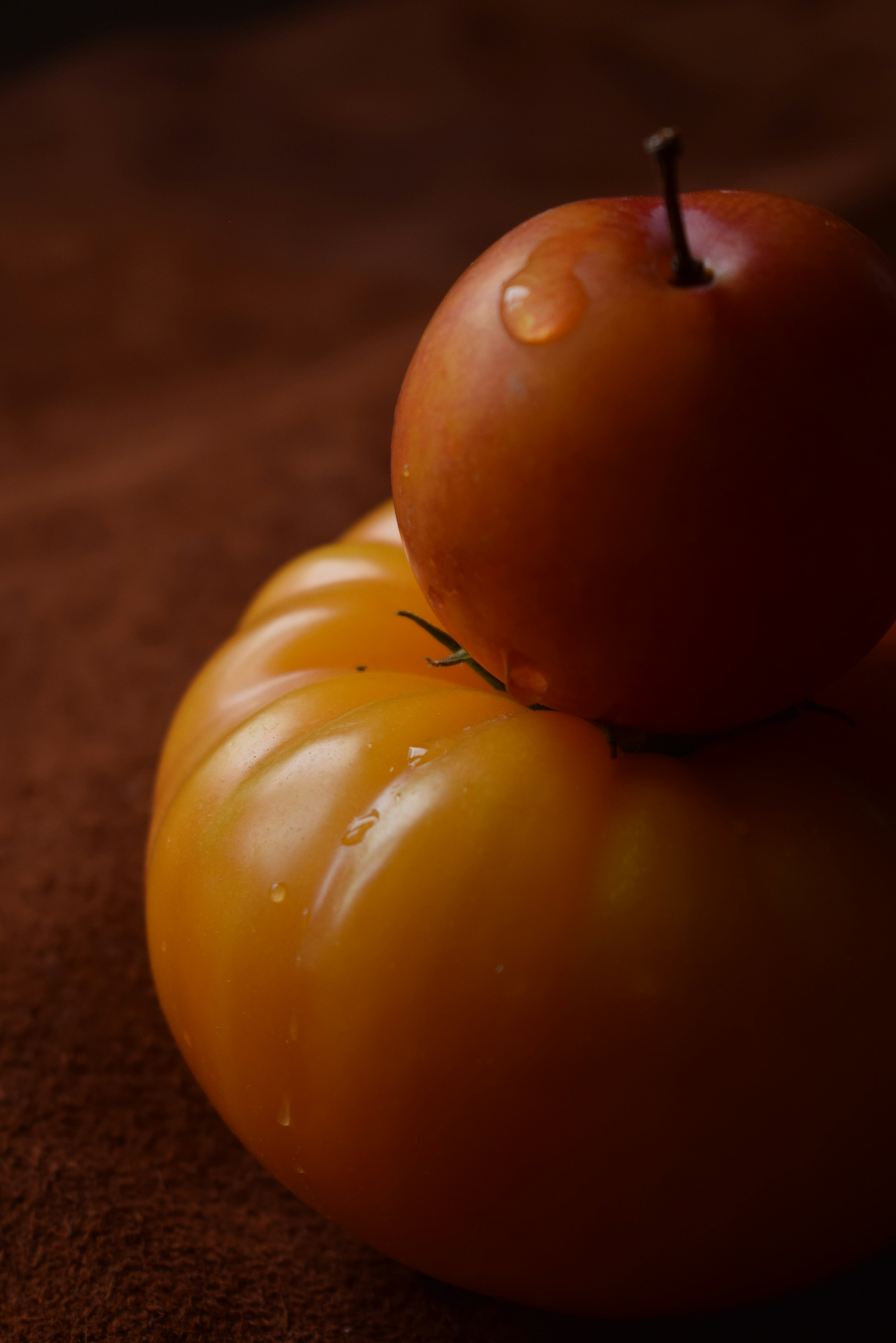 A ripe tomato with a plum on top