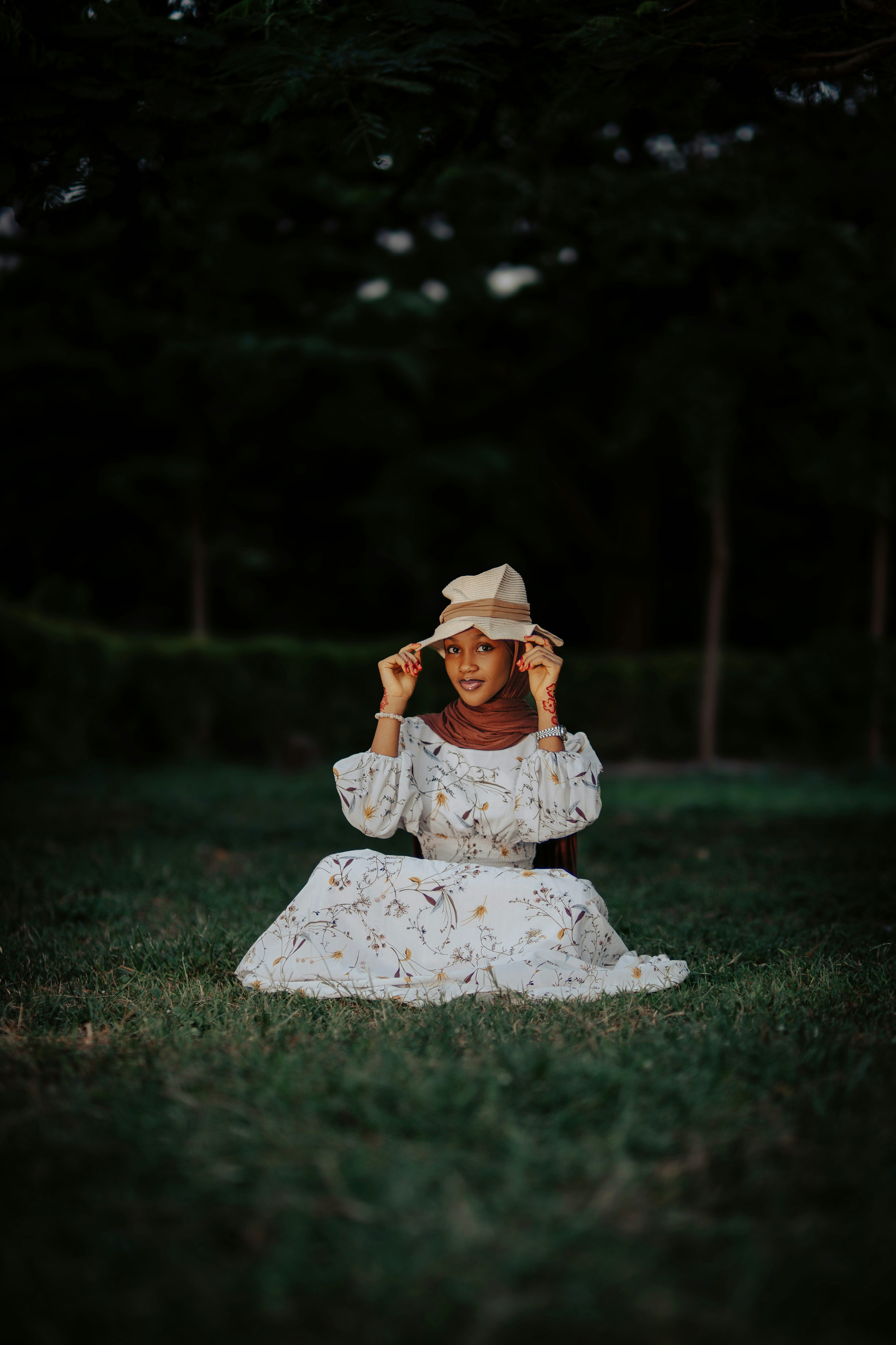 A minimalist shot of natural light falling across a textured surface, highlighting calm tones and details. | Young girl in hat sitting on grassy field