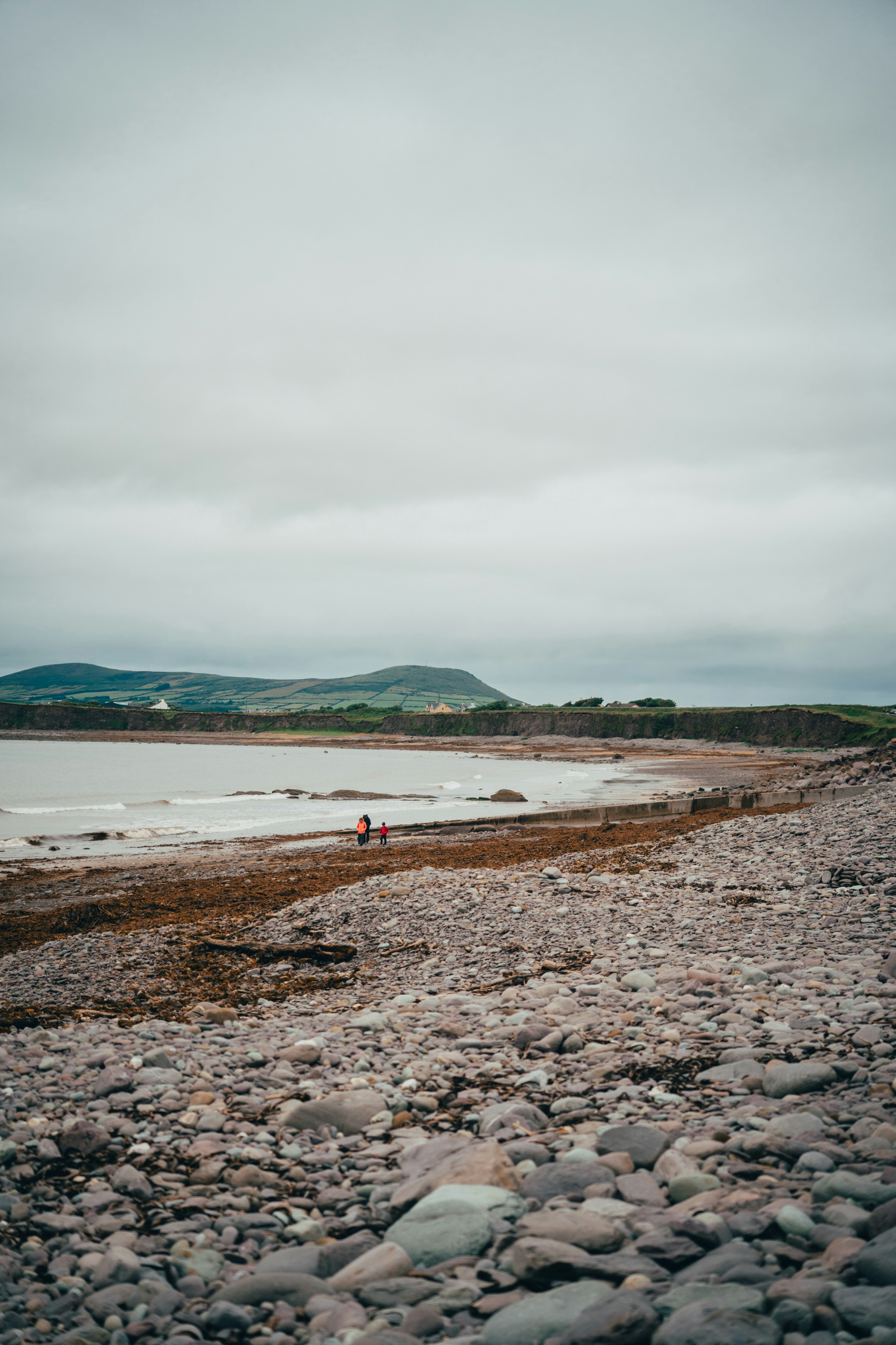 Pebble beach with two people near the water.