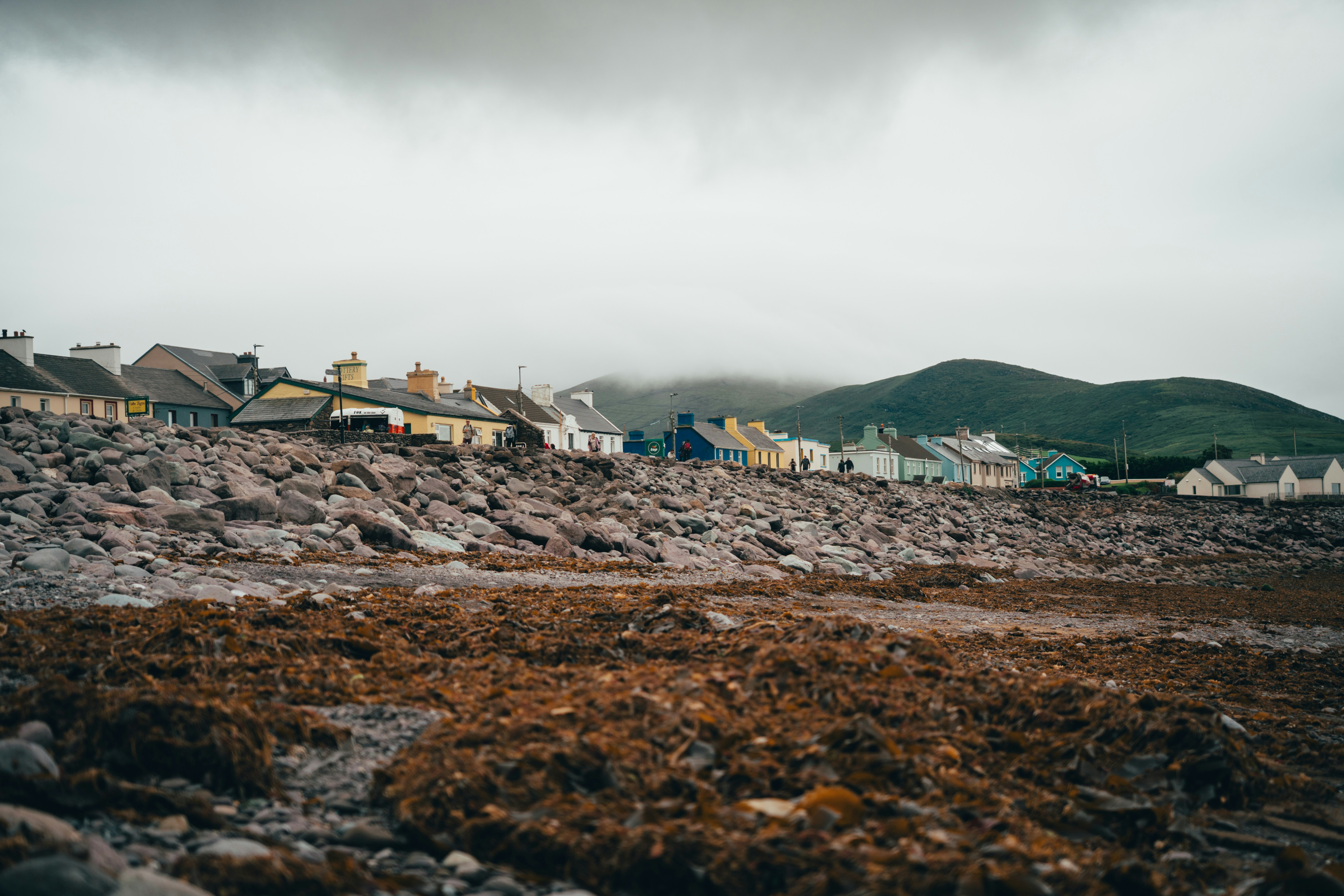 Colorful houses line a rocky shore under cloudy skies.