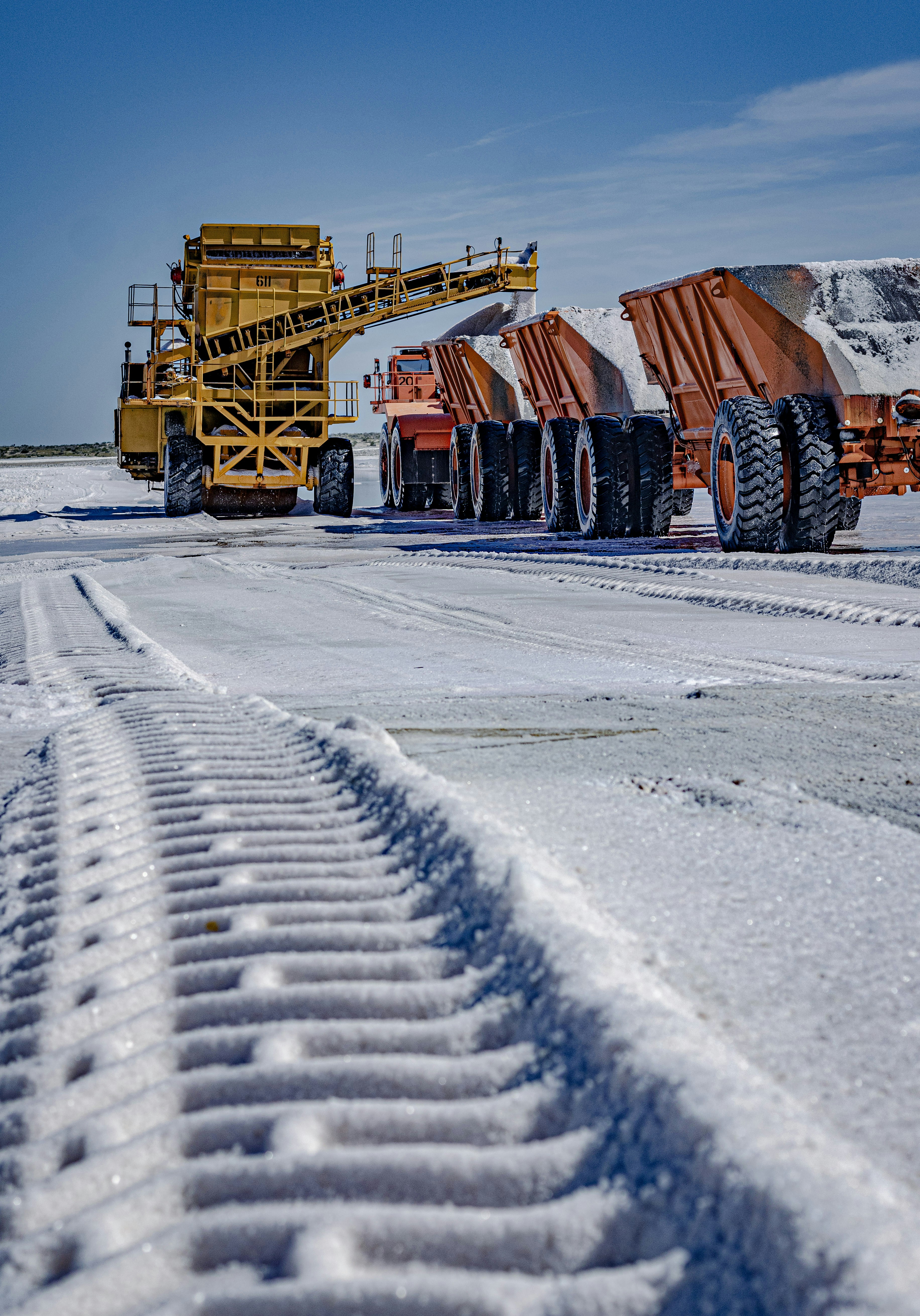 Large yellow mining equipment next to orange trucks