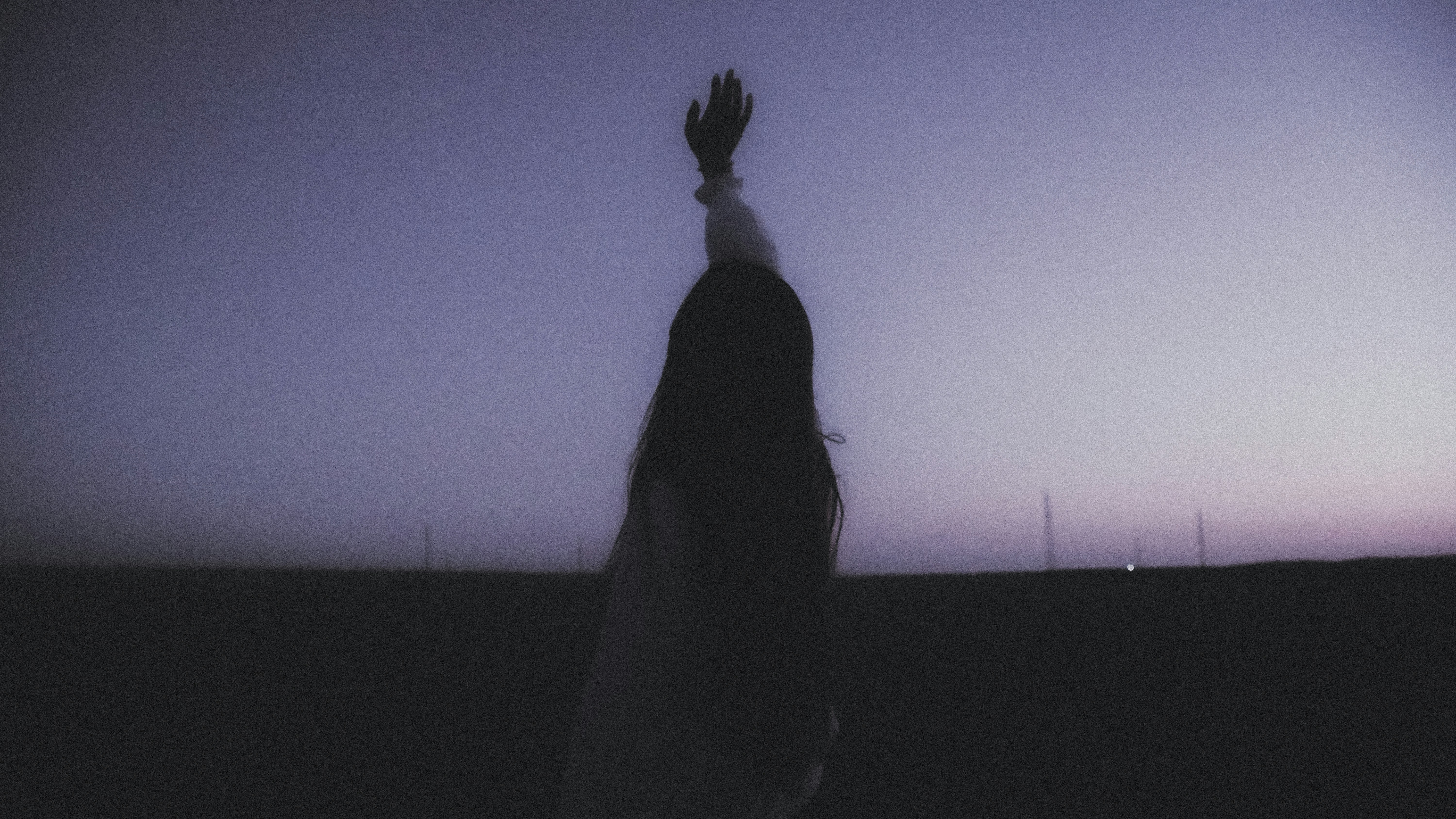 Silhouette of a person reaching up at dusk