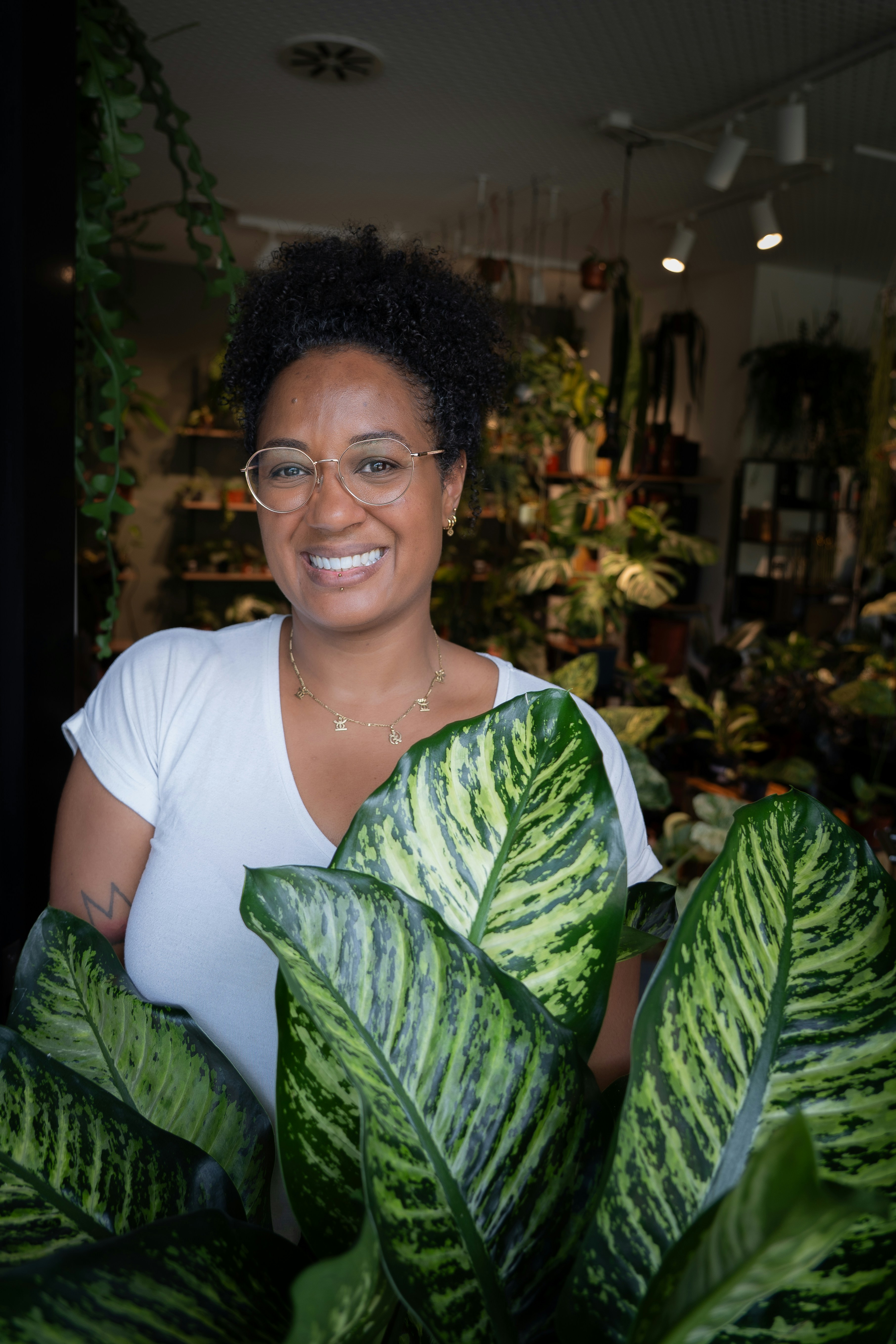 Bright Portrait Amid Greenery: A Friendly Smile in a Plant Haven
