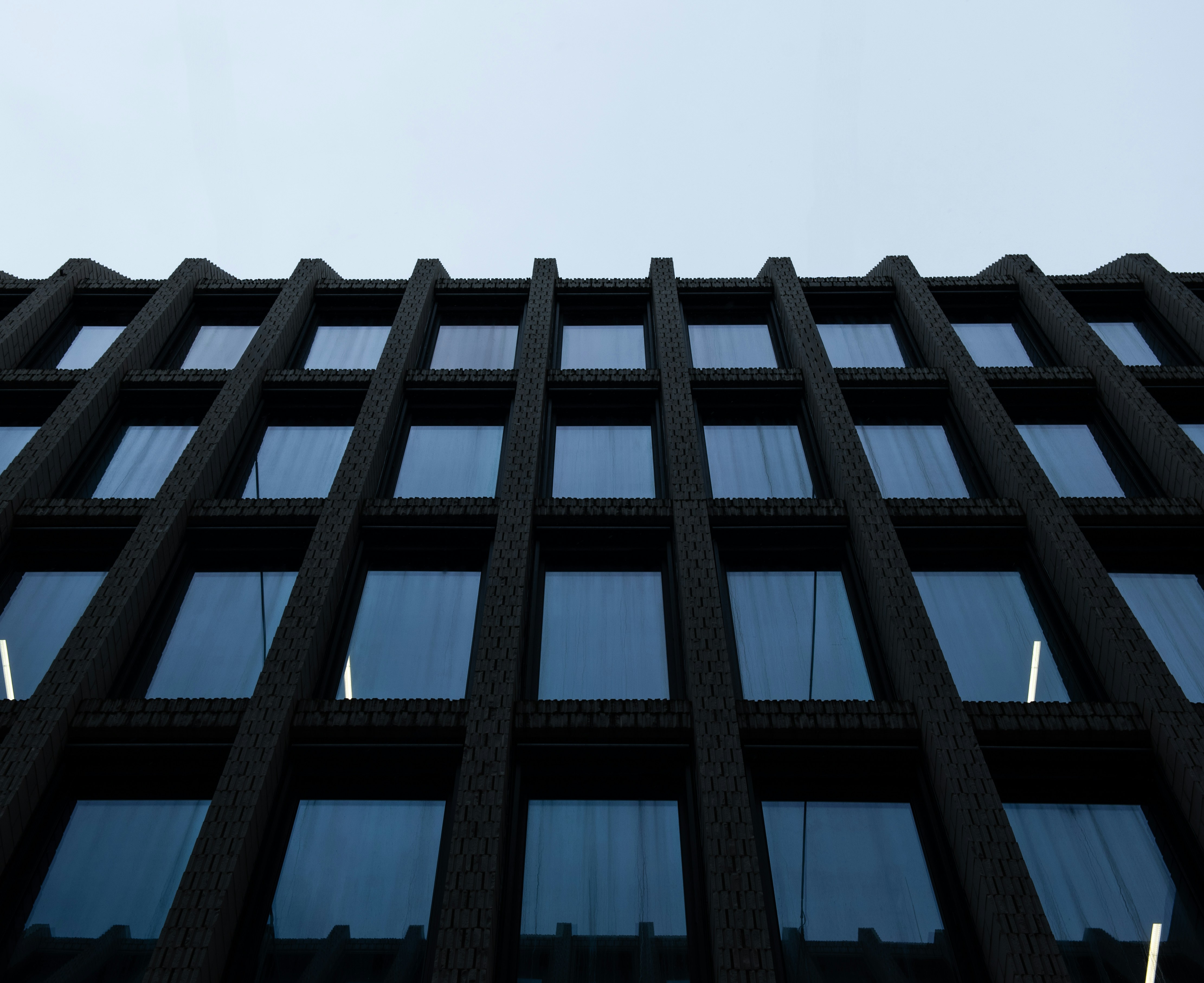 Modern building facade with repeating windows and dark brick