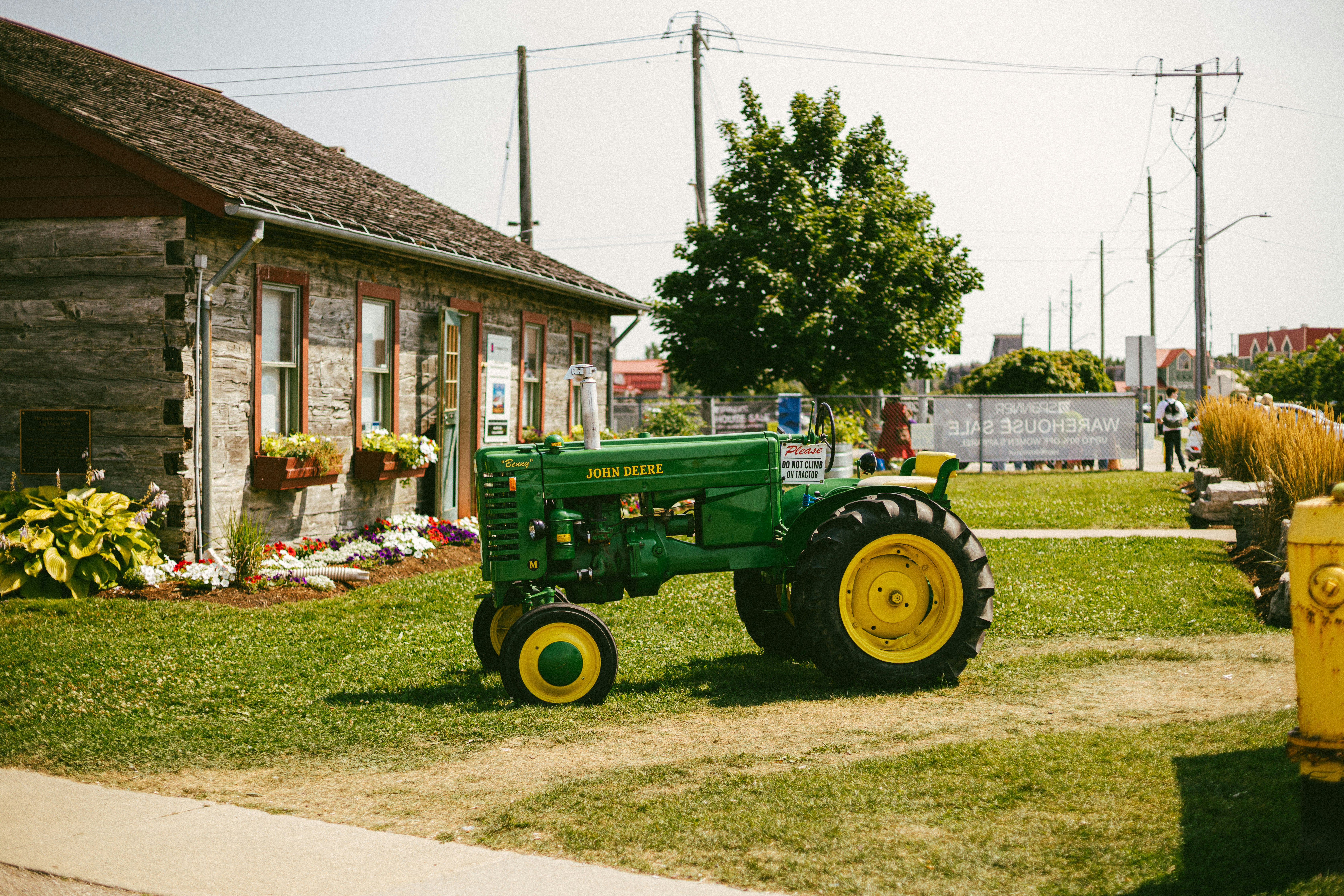 Green john deere tractor parked by wooden building.