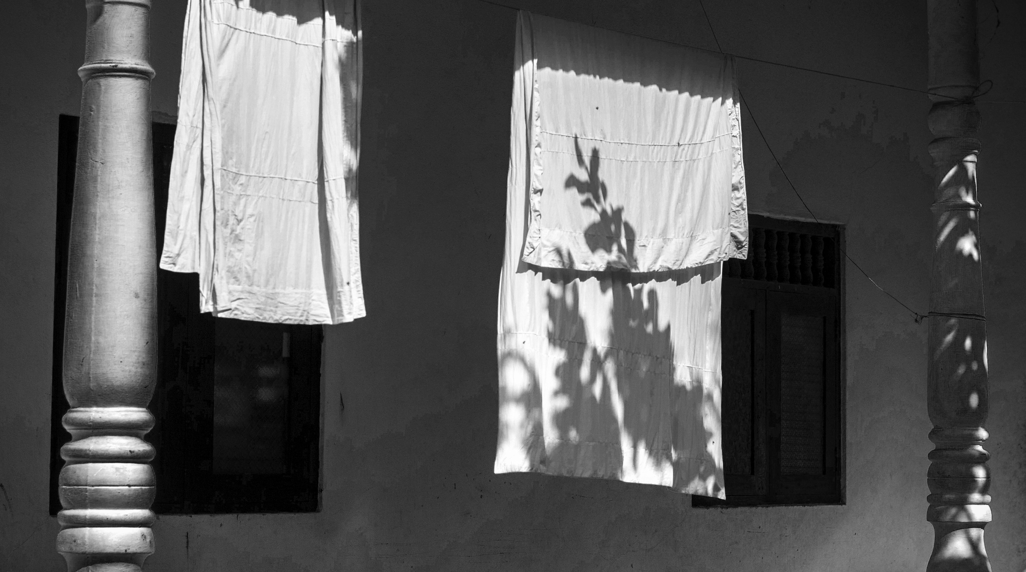 White clothes hanging on a line with shadows.