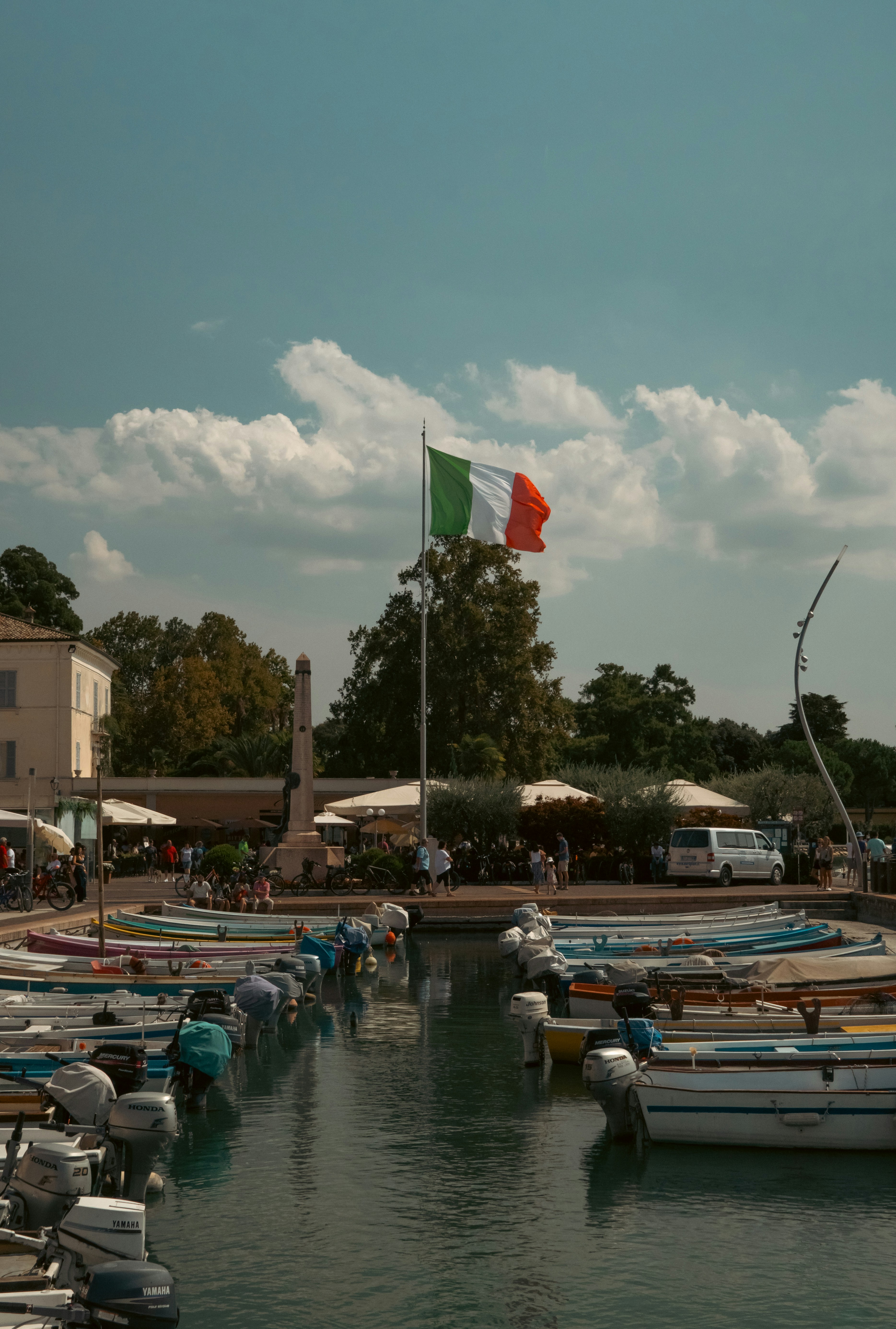 Italian flag flies over boats docked in harbor.