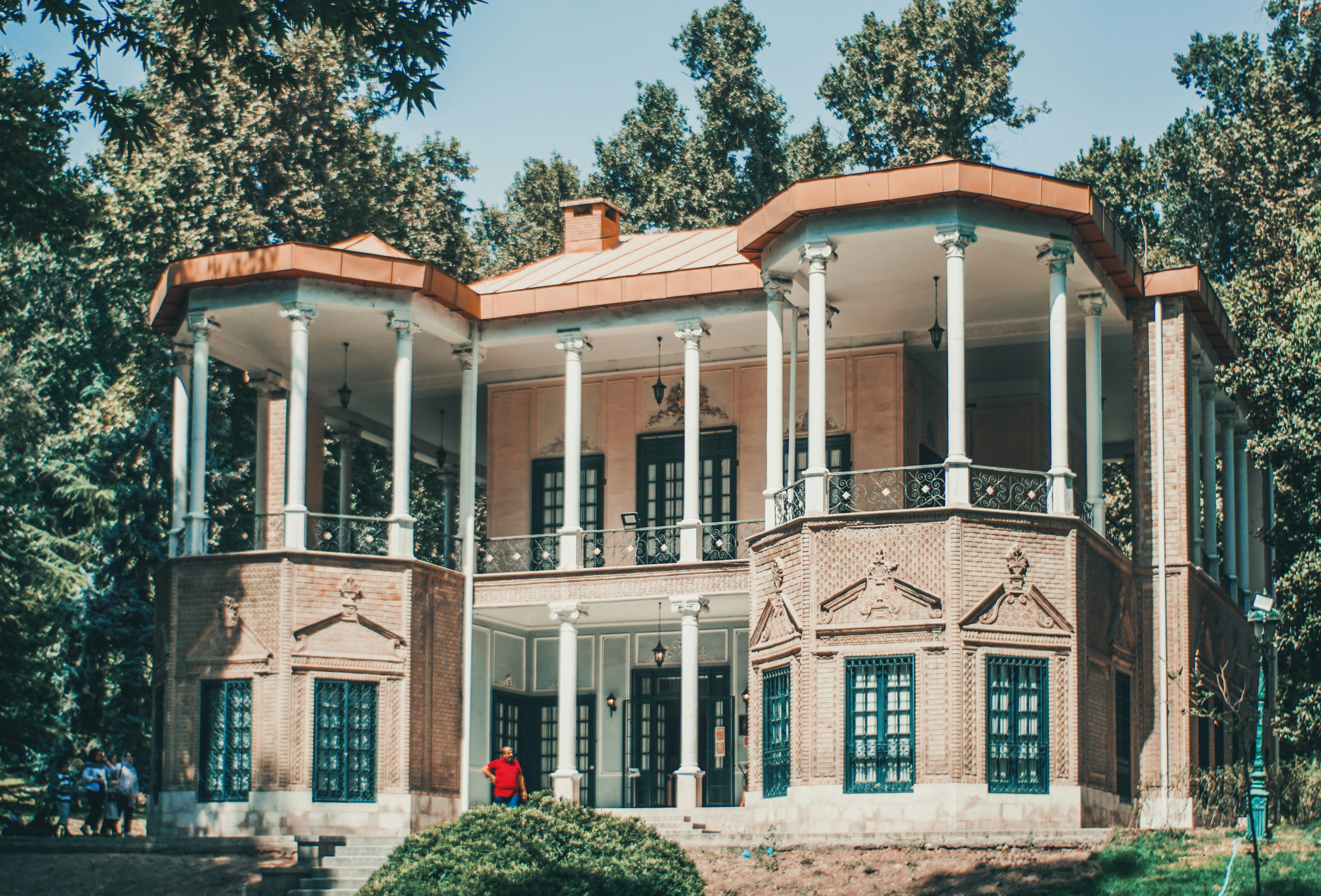 The silent symphony of a peaceful afternoon. | Historic mansion with columns surrounded by trees.