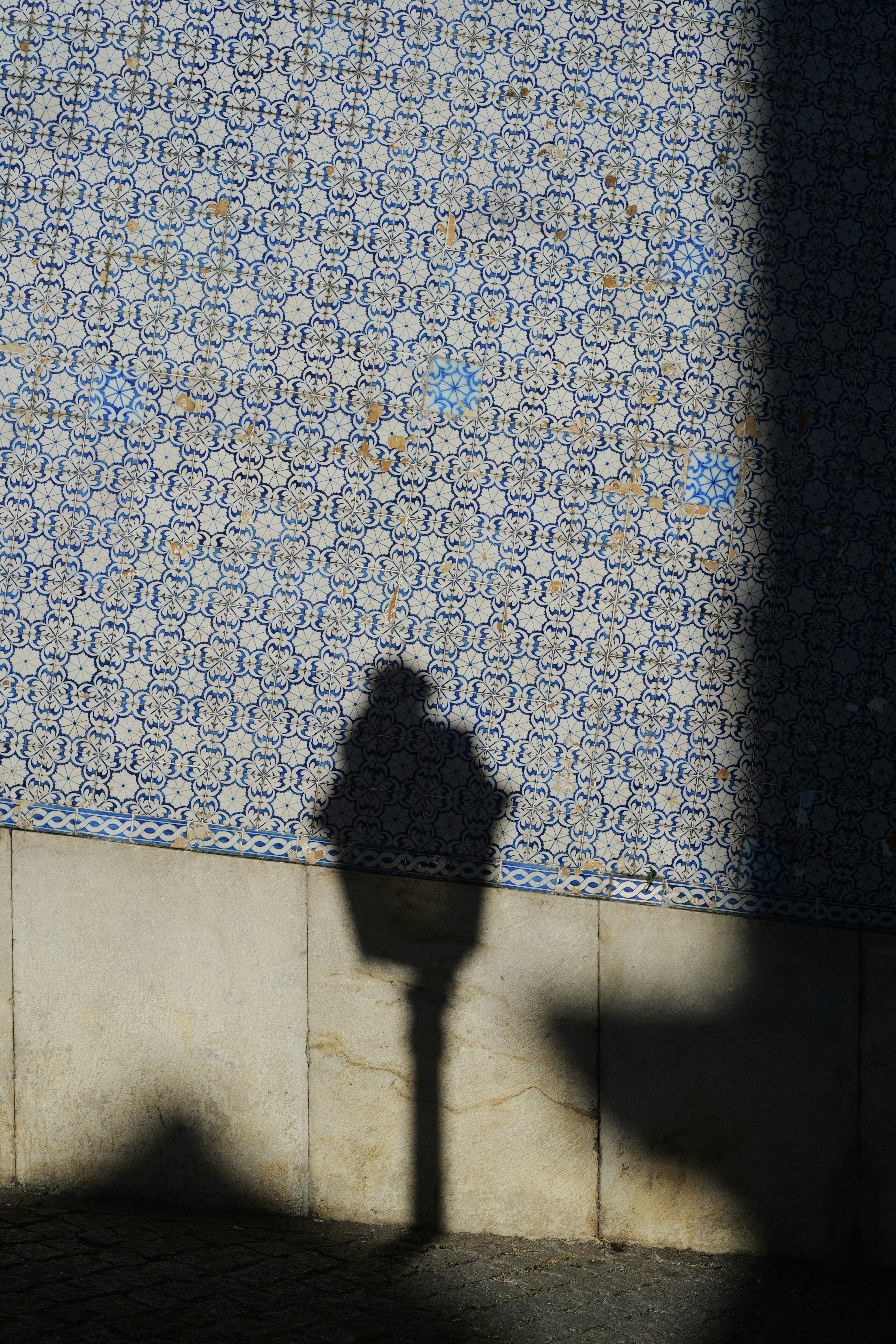 Tiles, lisbon, city center | Shadow of a lamppost on a tiled wall