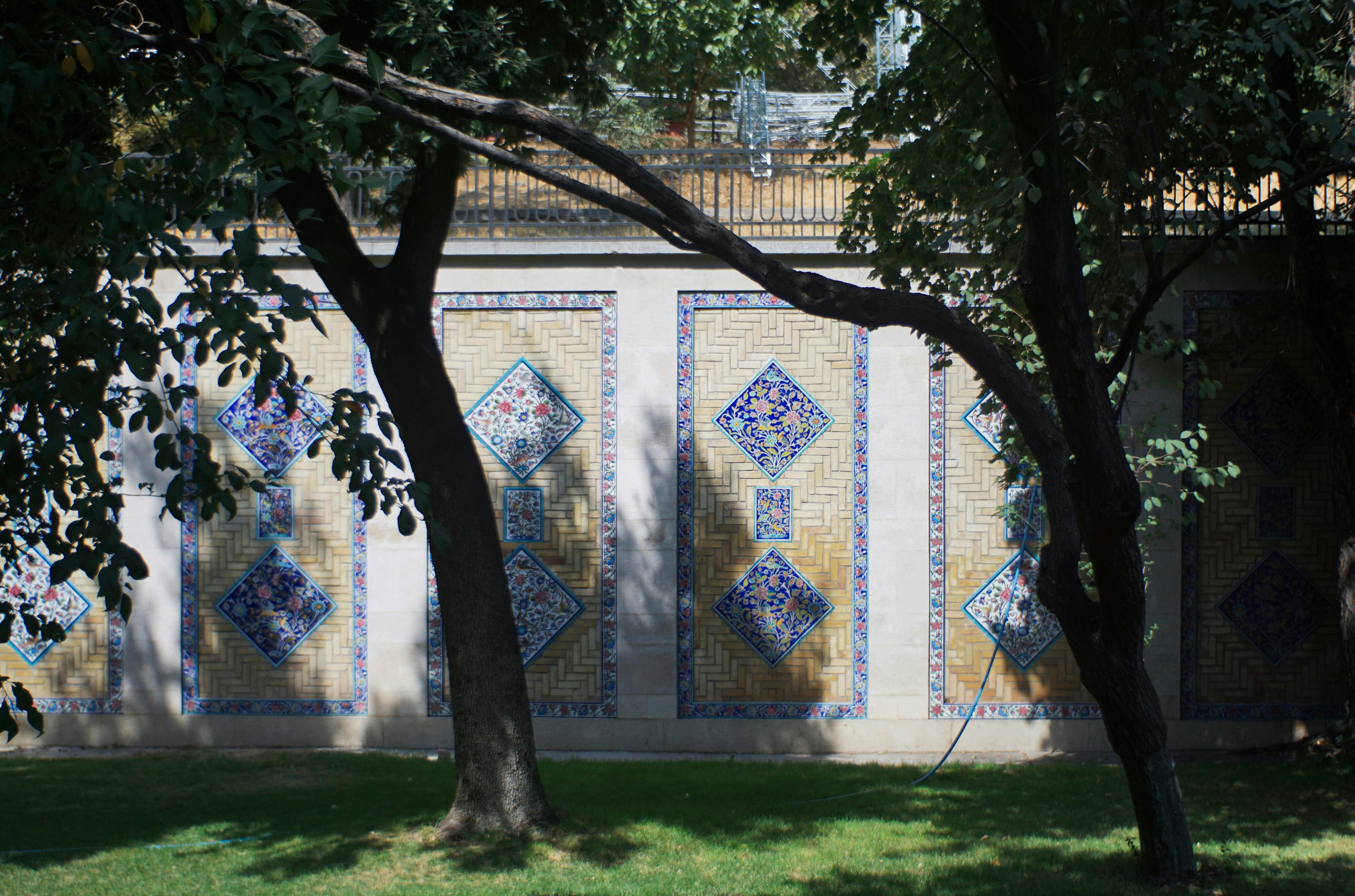 Ornate tiled wall with trees in foreground.