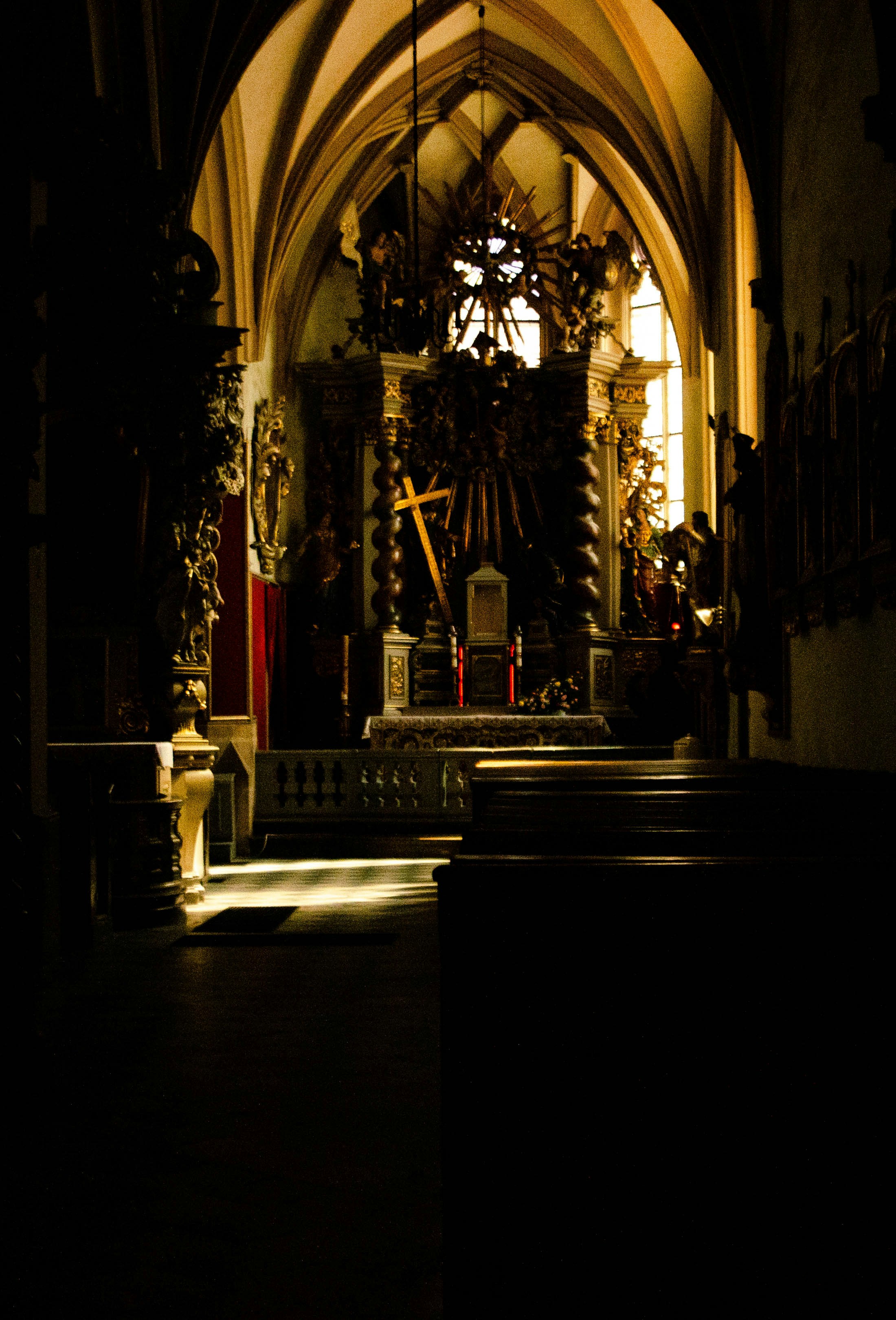 Sunlight streams into a dark, ornate church altar.