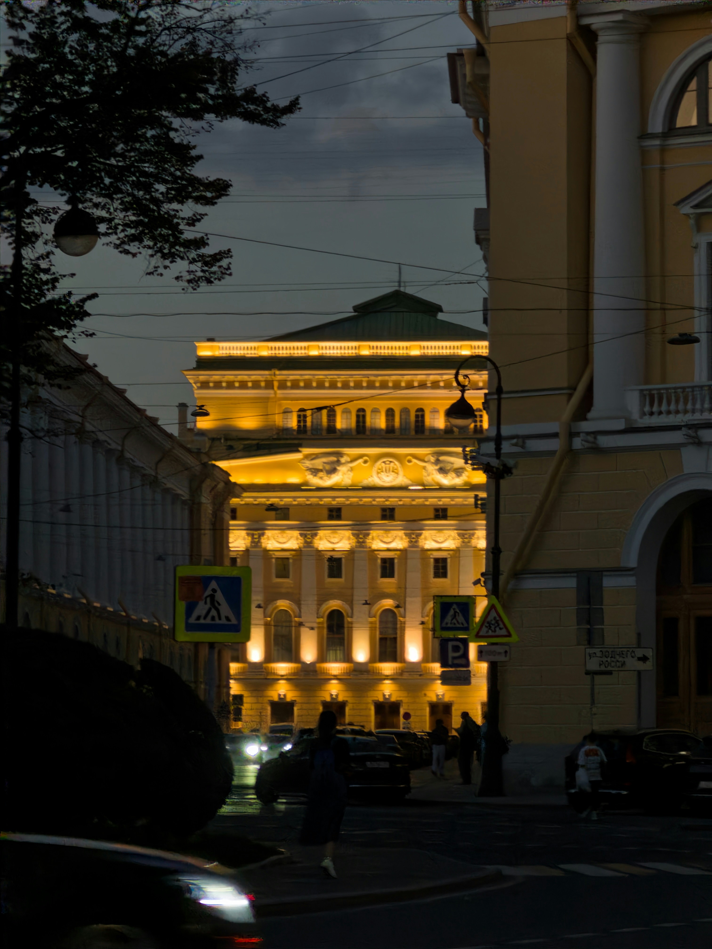 Ornate building illuminated at dusk on city street.