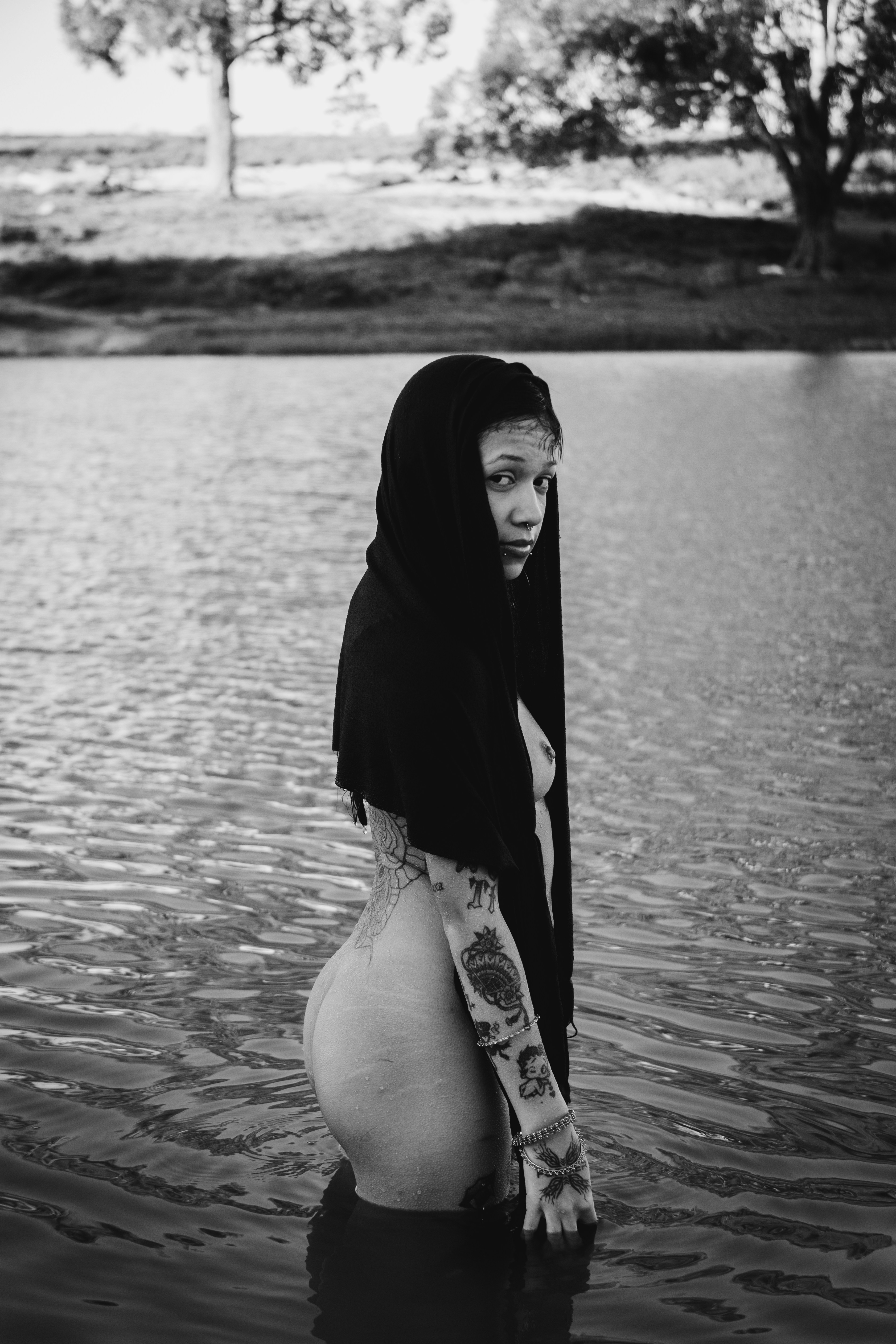 Tattooed woman in black headscarf standing in water